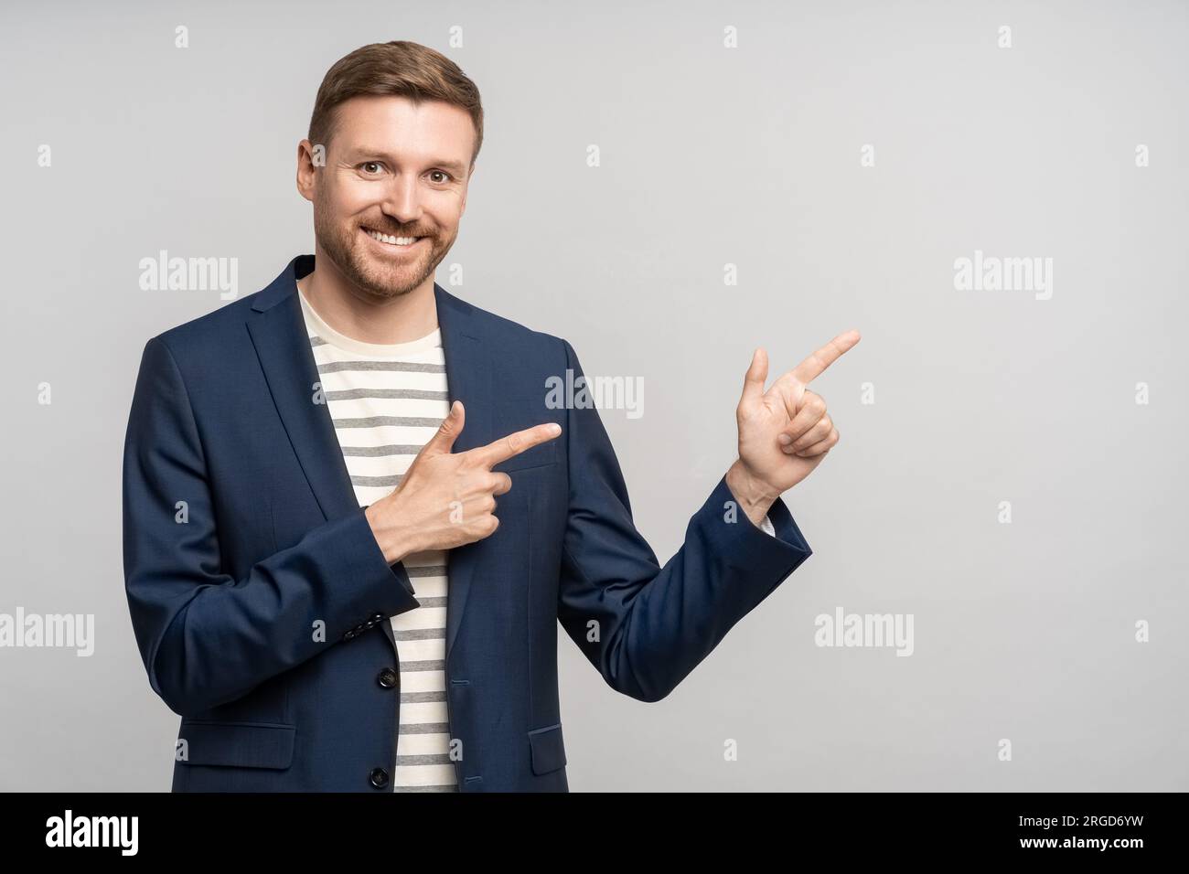 Positive businessman promoter points with index fingers on empty space ...