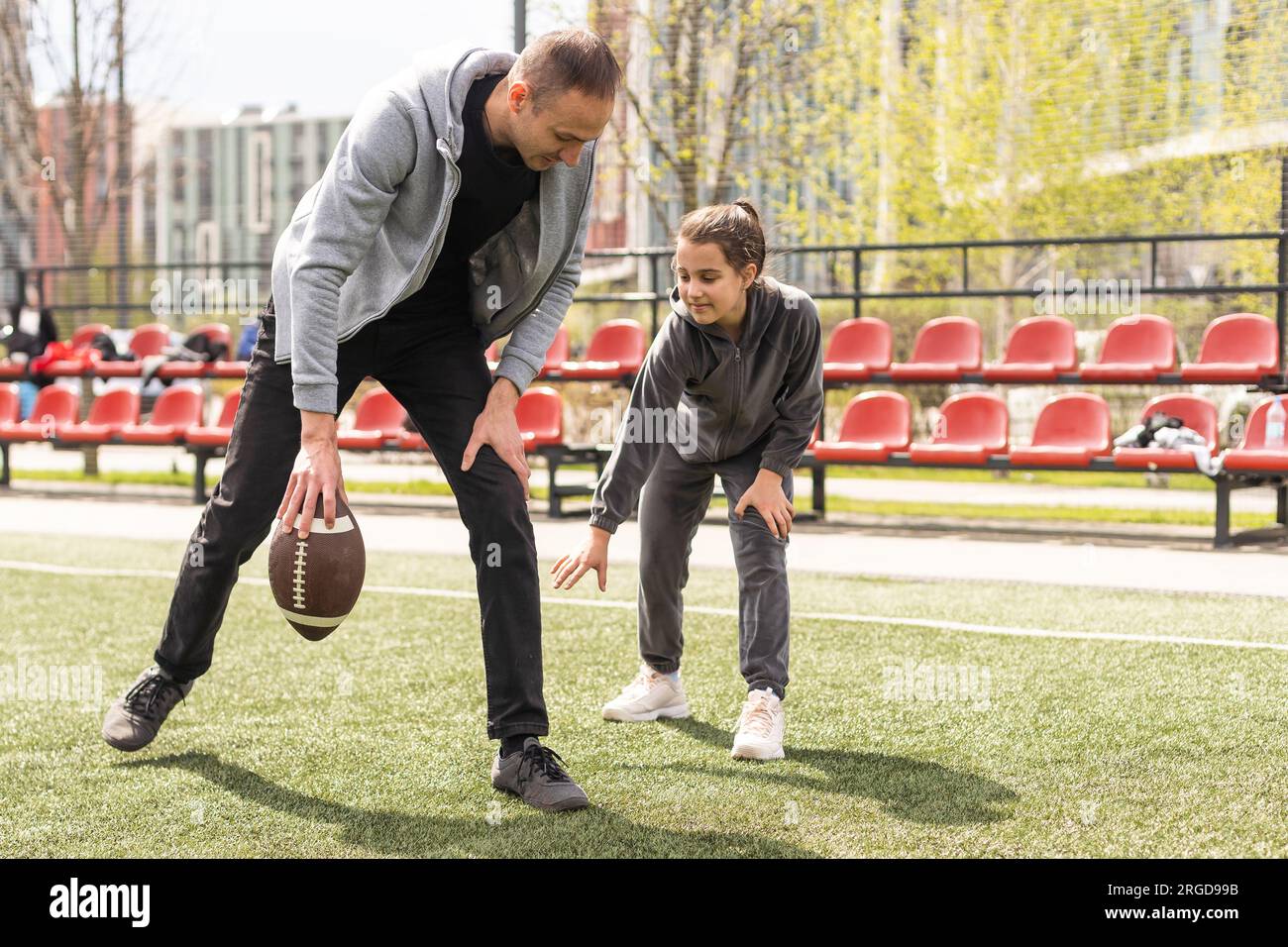 girl holding an oval brown leather rugby ball and smiling while playing ...