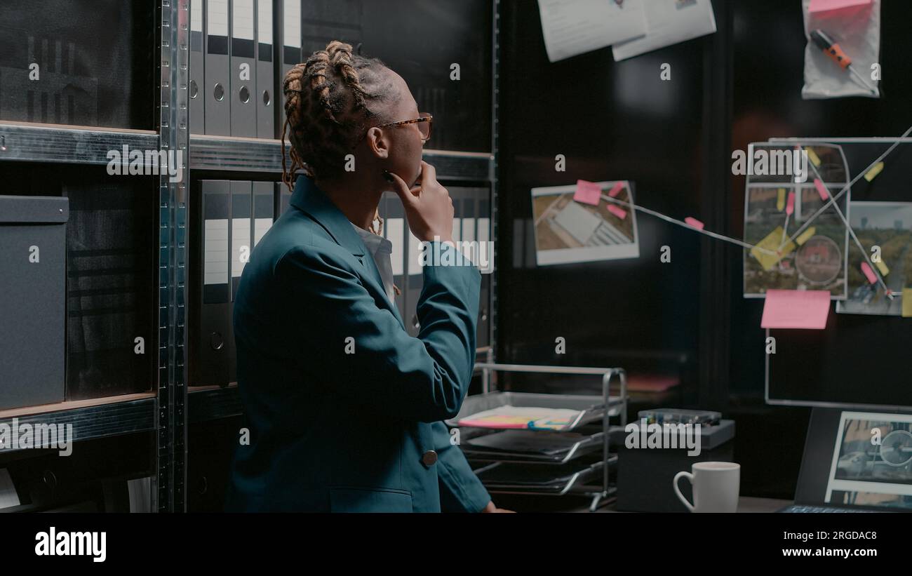 Female detective examining board with clues and research to solve ...