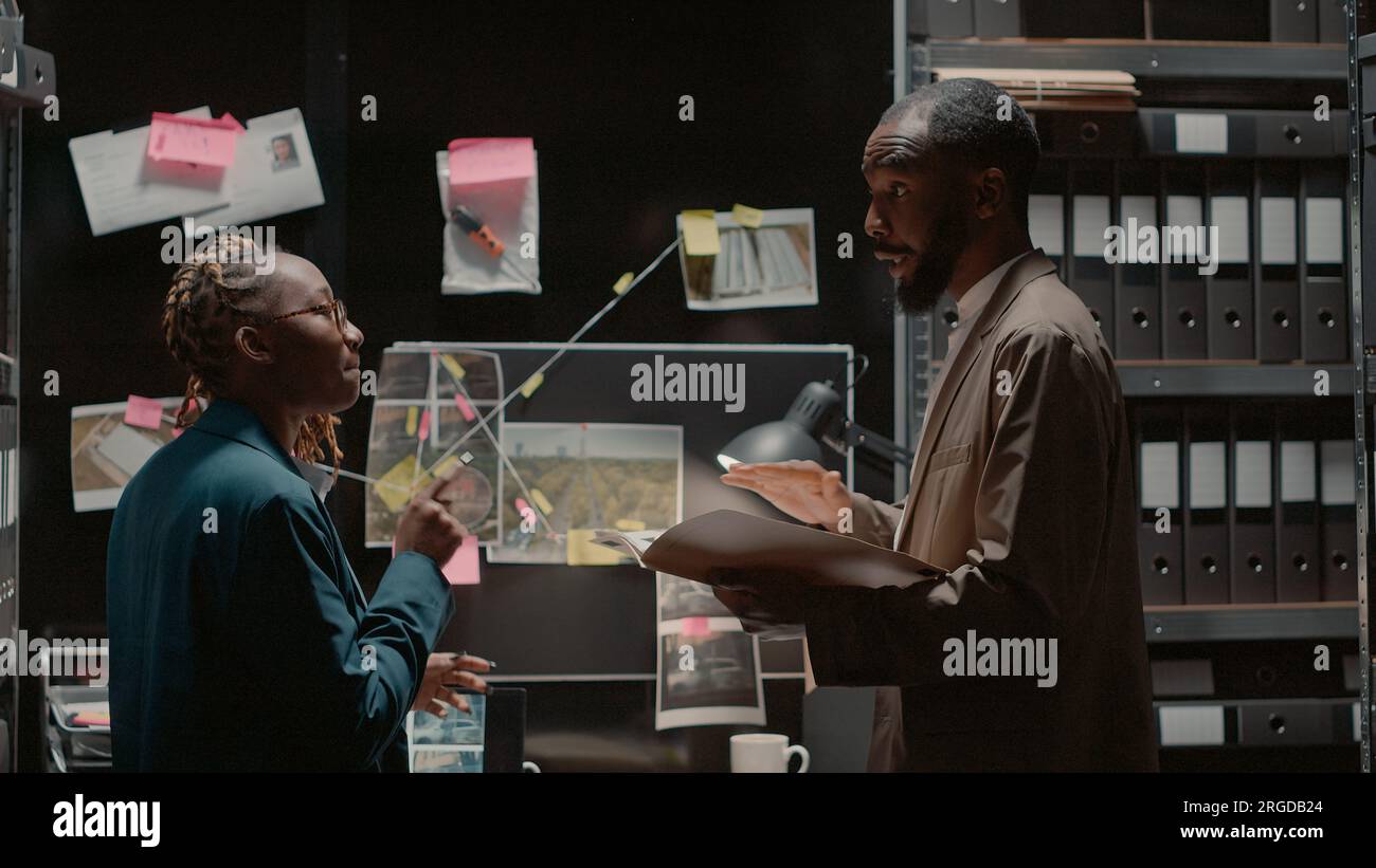 Detectives colleagues examining criminal files in office, looking at ...