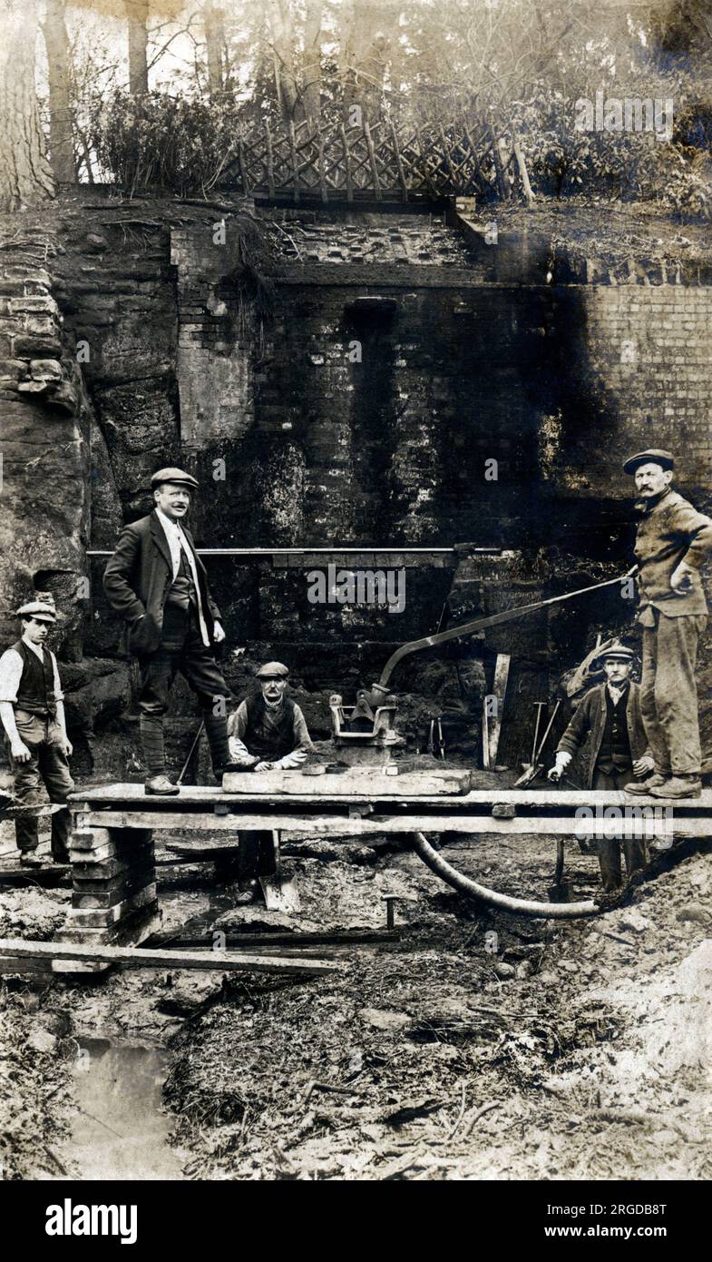 Hand pump being used to drain water out from a small seam of tin ...