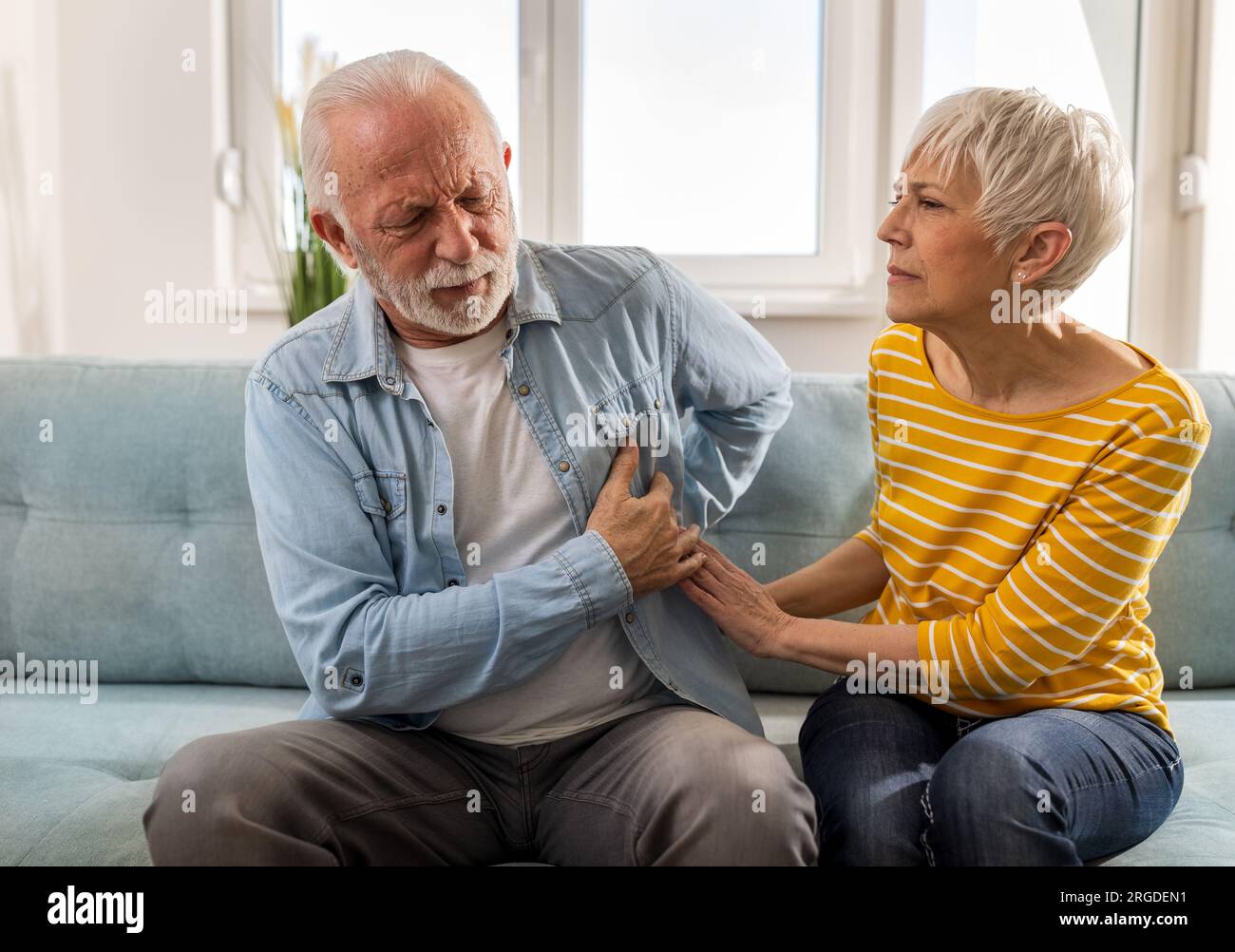 Mature woman comforting worried husband on sofa in living room by ...