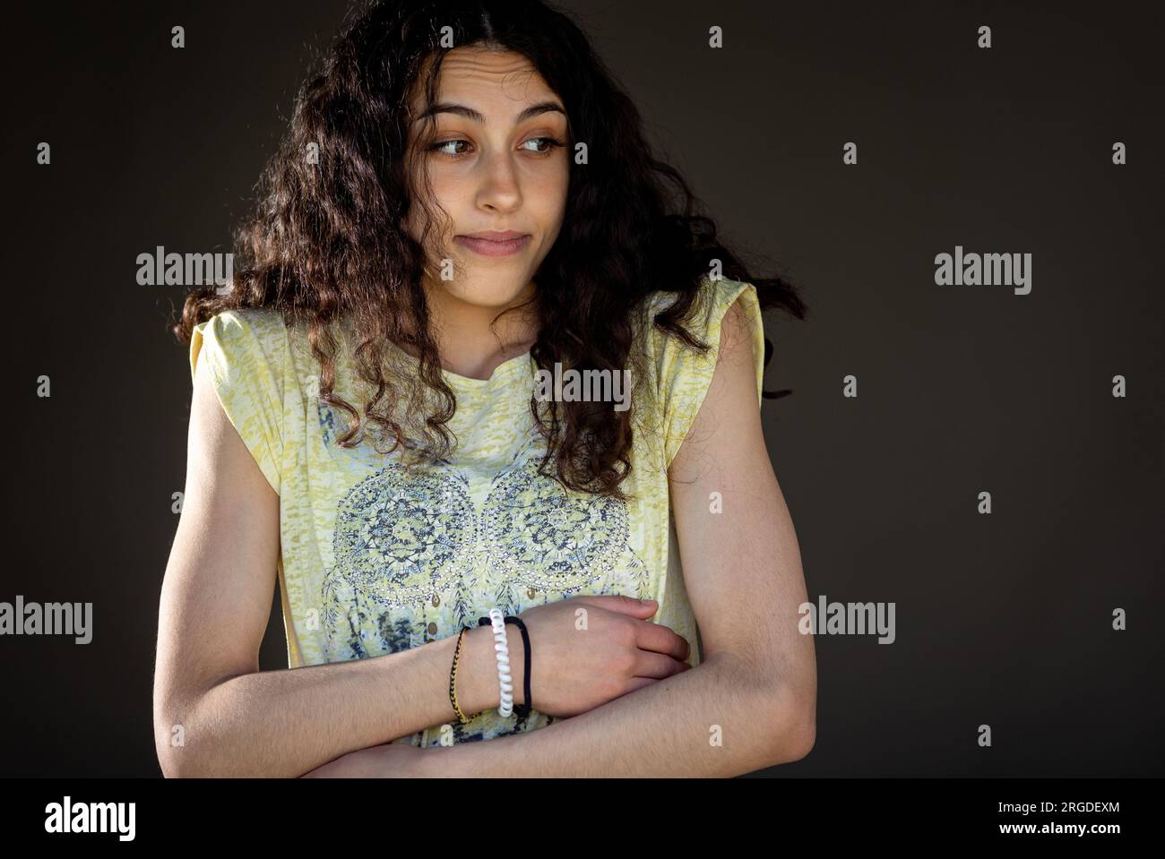 Pretty young confused girl standing with crossed arms in studio with ...