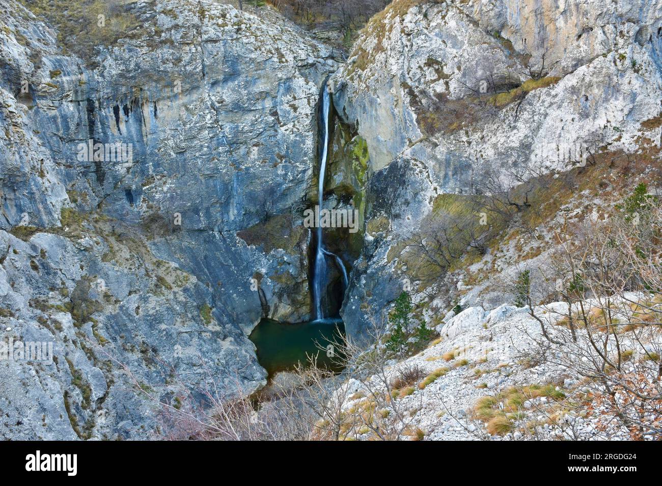 Waterfall carved into a rock wall falling into a pool in Val Rosandra ...