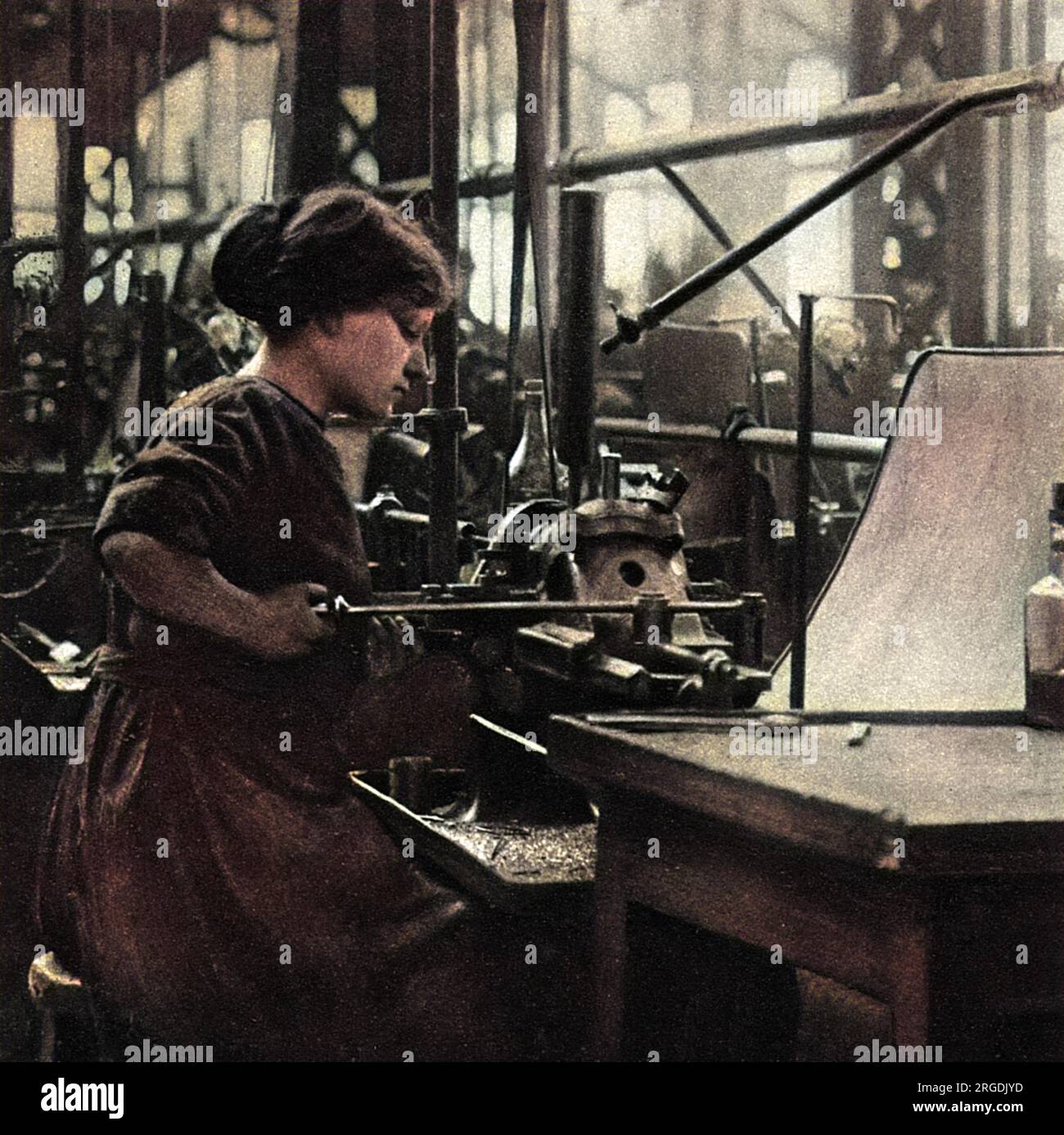 French lady as she sits at her bench, in a French factory, machining ...
