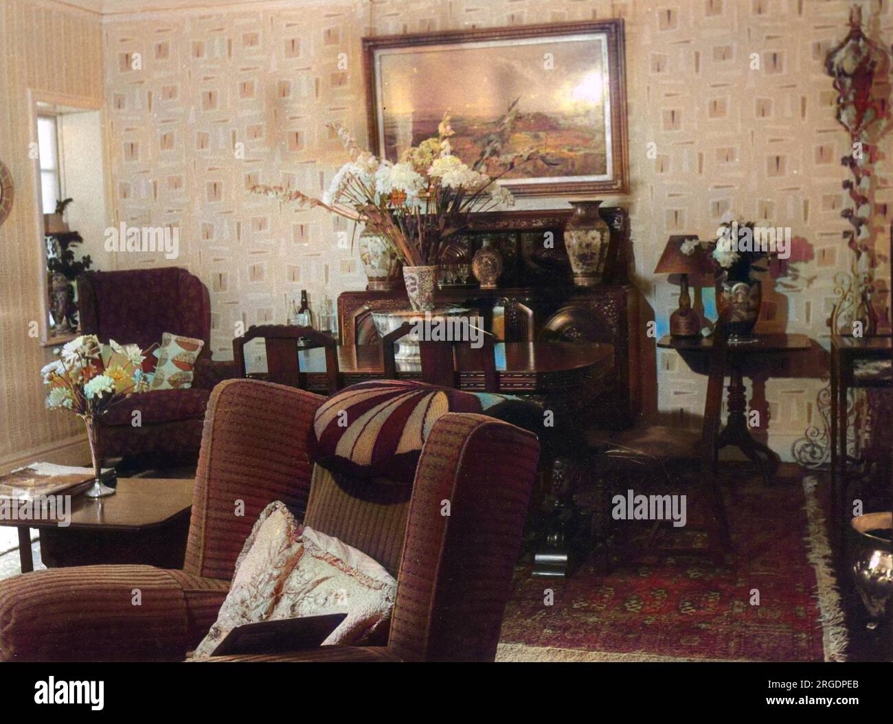 A traditional English lounge interior, with comfy armchairs and a vase ...