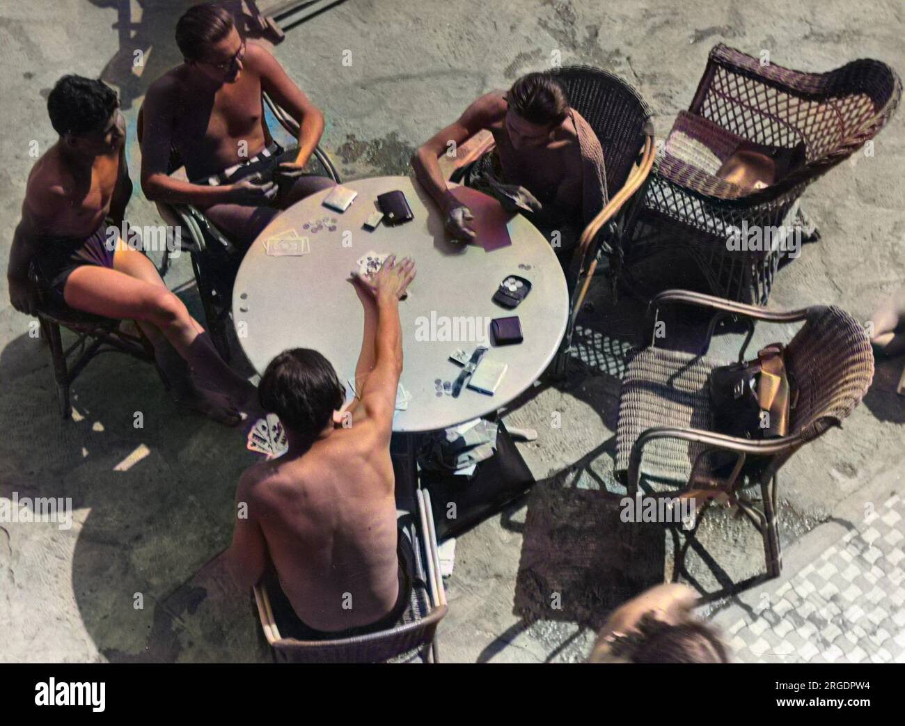 Four young men playing a game of cards at a round table Stock Photo - Alamy