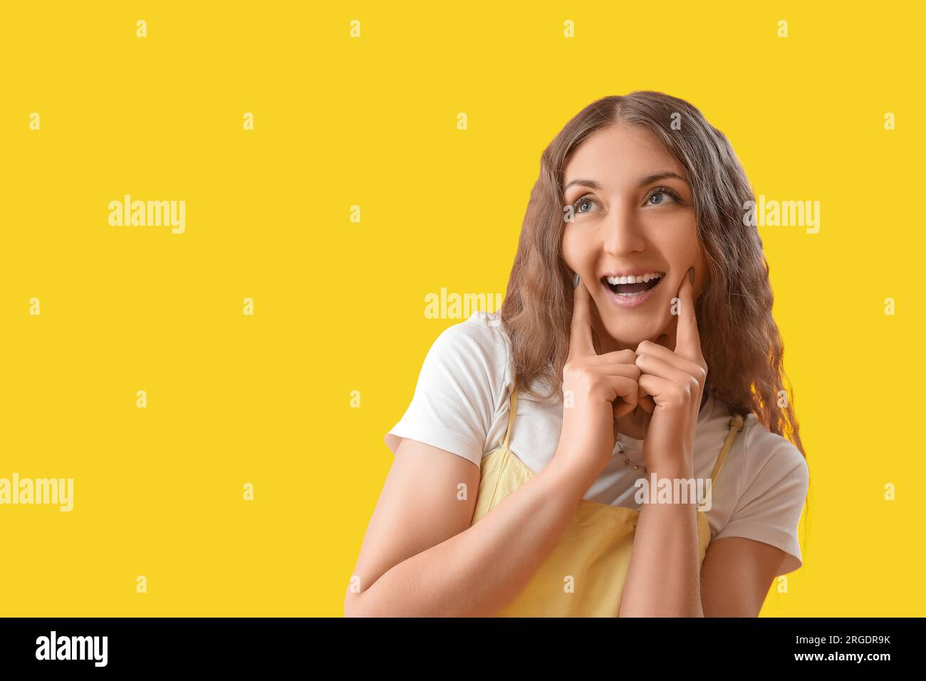 Happy young woman touching her cheeks on yellow background Stock Photo ...