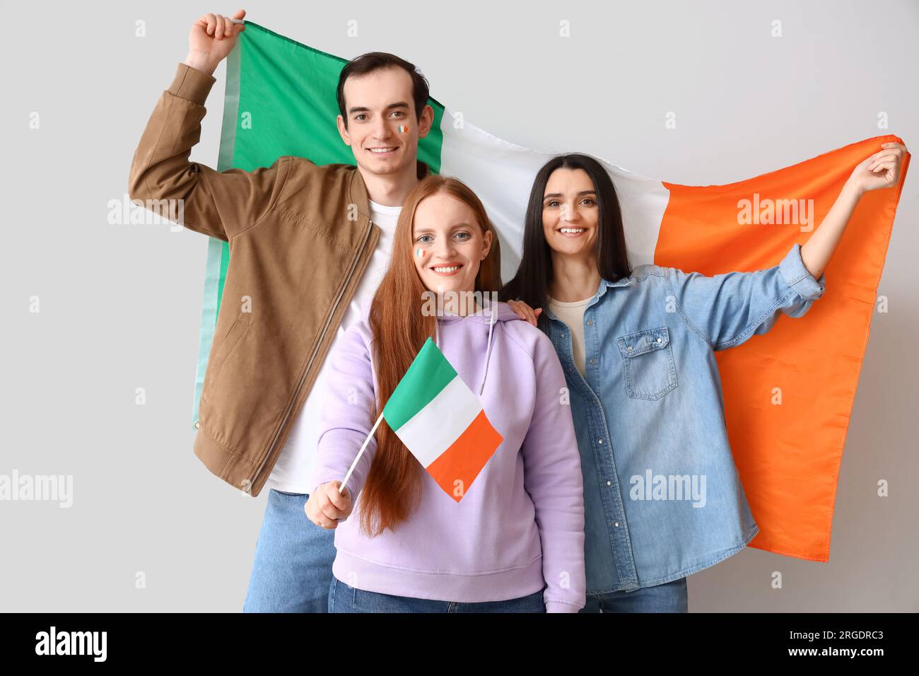Happy friends with flags of Ireland on light background Stock Photo - Alamy