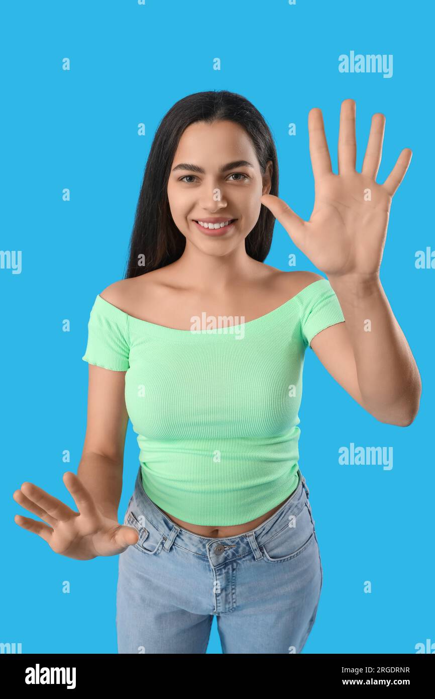 Beautiful young woman showing hands on blue background Stock Photo - Alamy