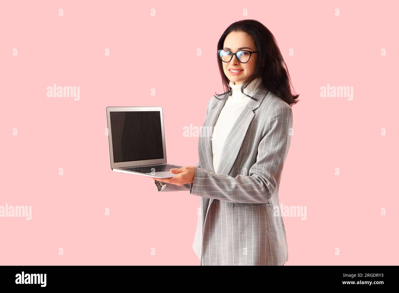 Female teacher of computer sciences with laptop on pink background ...