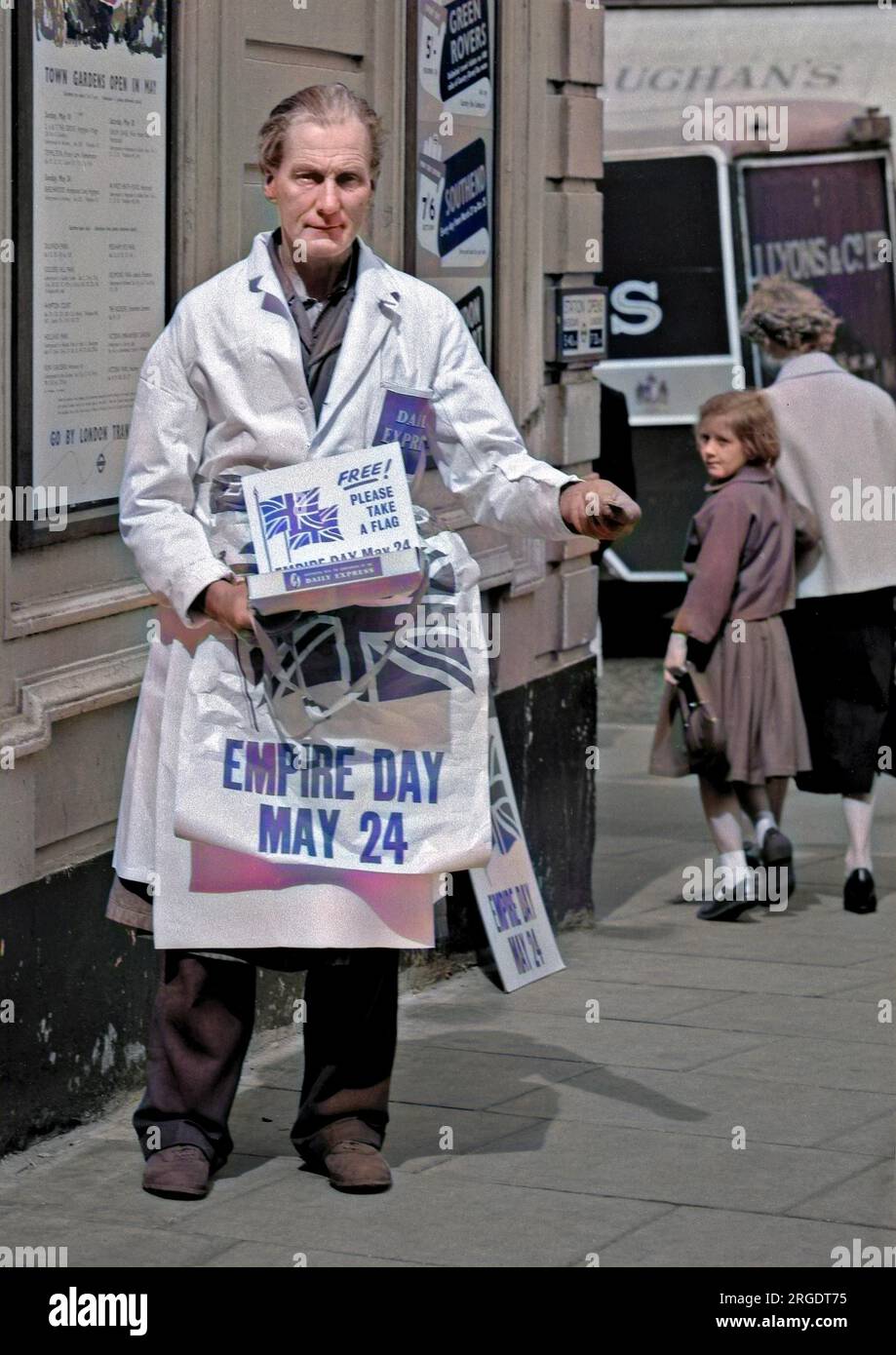A man standing on a street corner giving away Empire Day flags for the ...