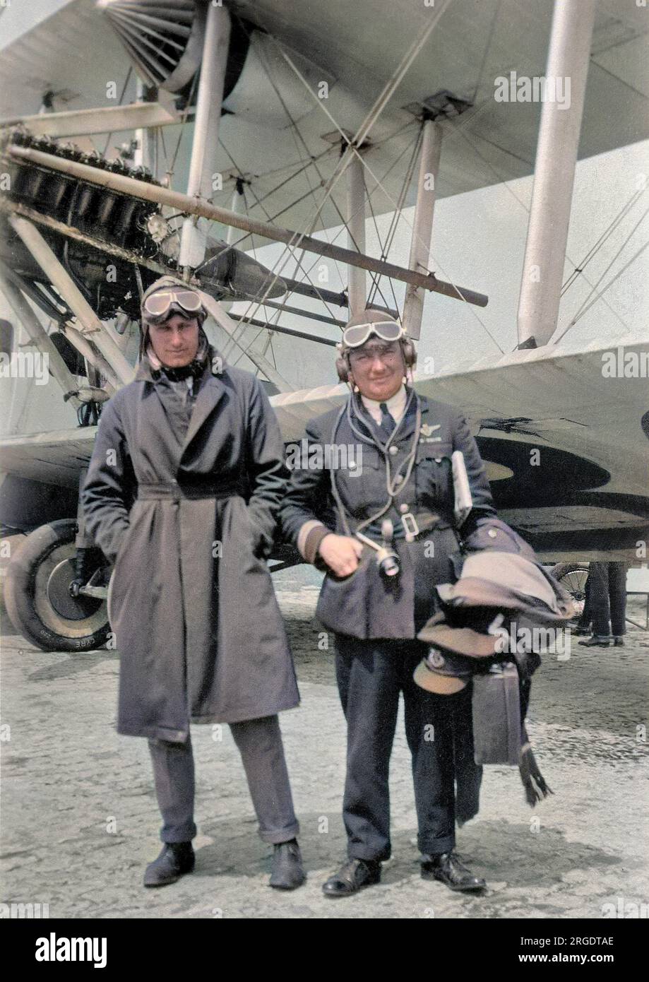 Two airmen in goggles standing in front of a large biplane Stock Photo ...
