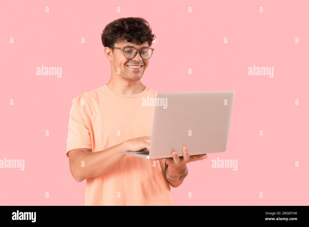 Male programmer working with computer on pink background Stock Photo ...