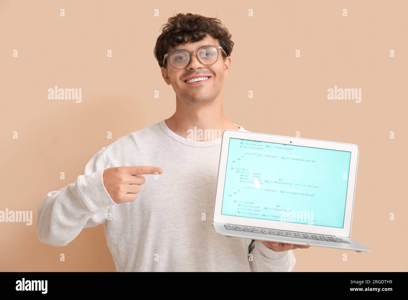 Male programmer pointing at laptop on beige background Stock Photo - Alamy