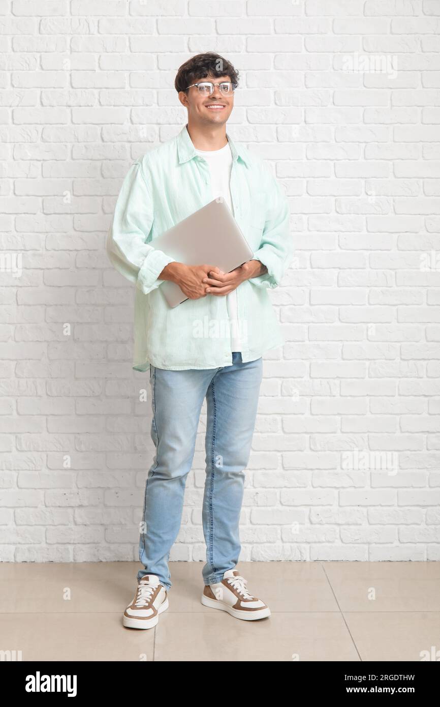 Male programmer with laptop near white brick wall Stock Photo - Alamy