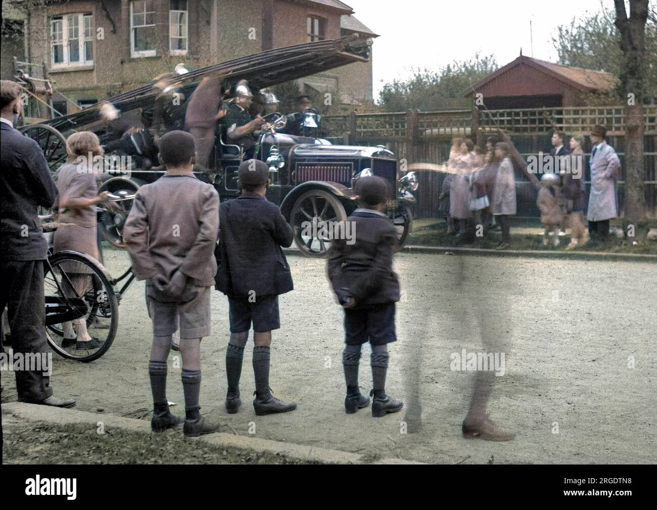 Street scene with people watching a fire engine racing past Stock Photo ...