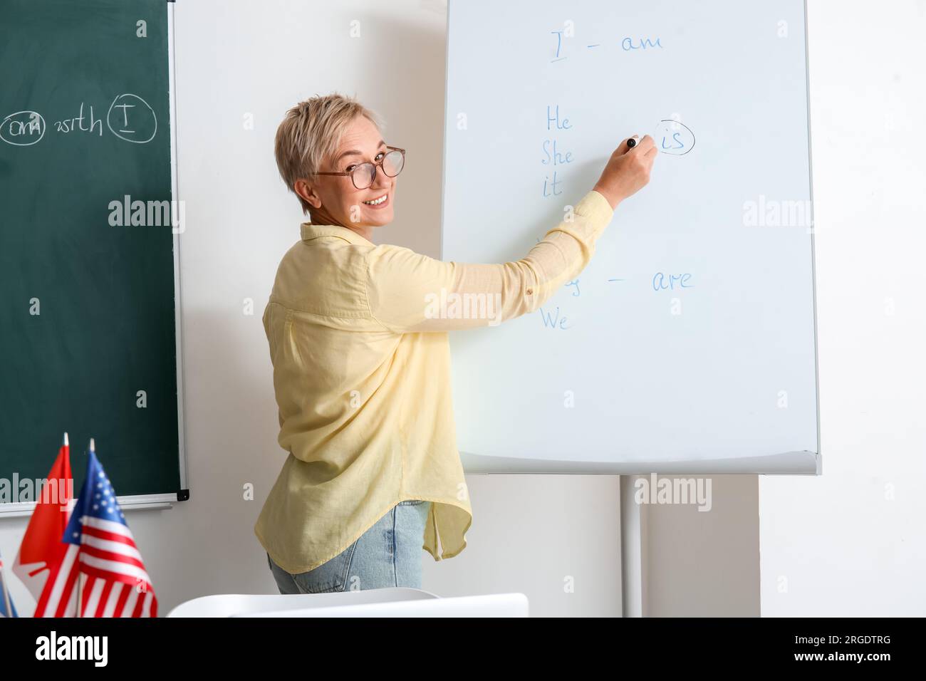 Female teacher writing English grammar on flipboard in classroom Stock ...