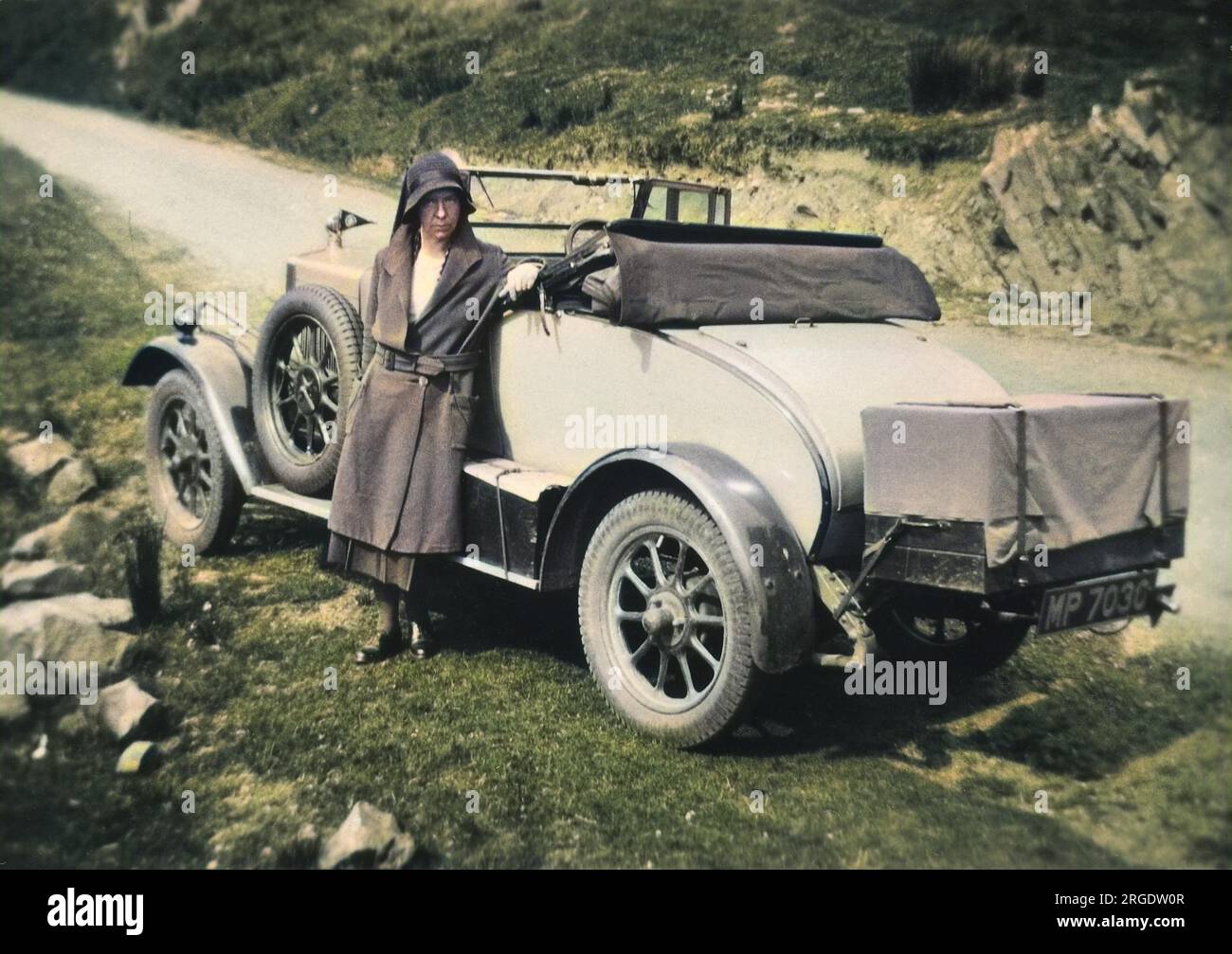 A woman standing in front of an open-topped car on a country road Stock ...
