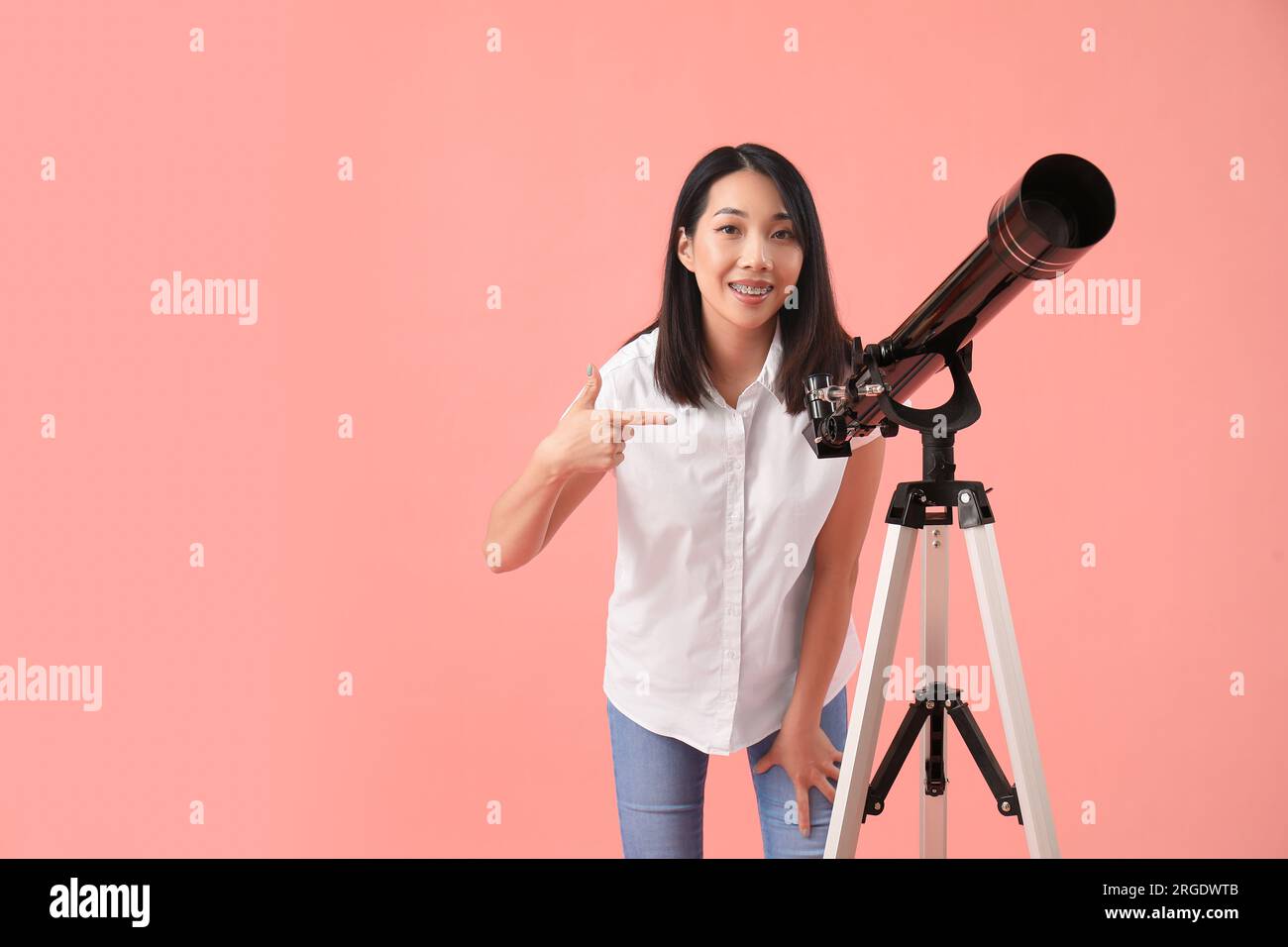 Young Asian woman using telescope on pink background Stock Photo - Alamy