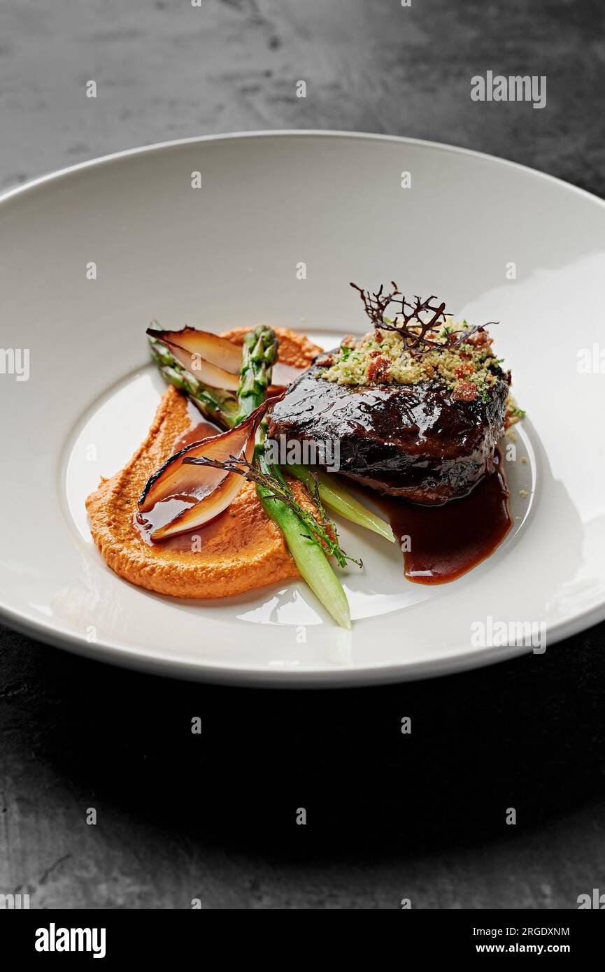 Slow-cooked beef cheek, charred shallots, asparagus spears, romesco ...
