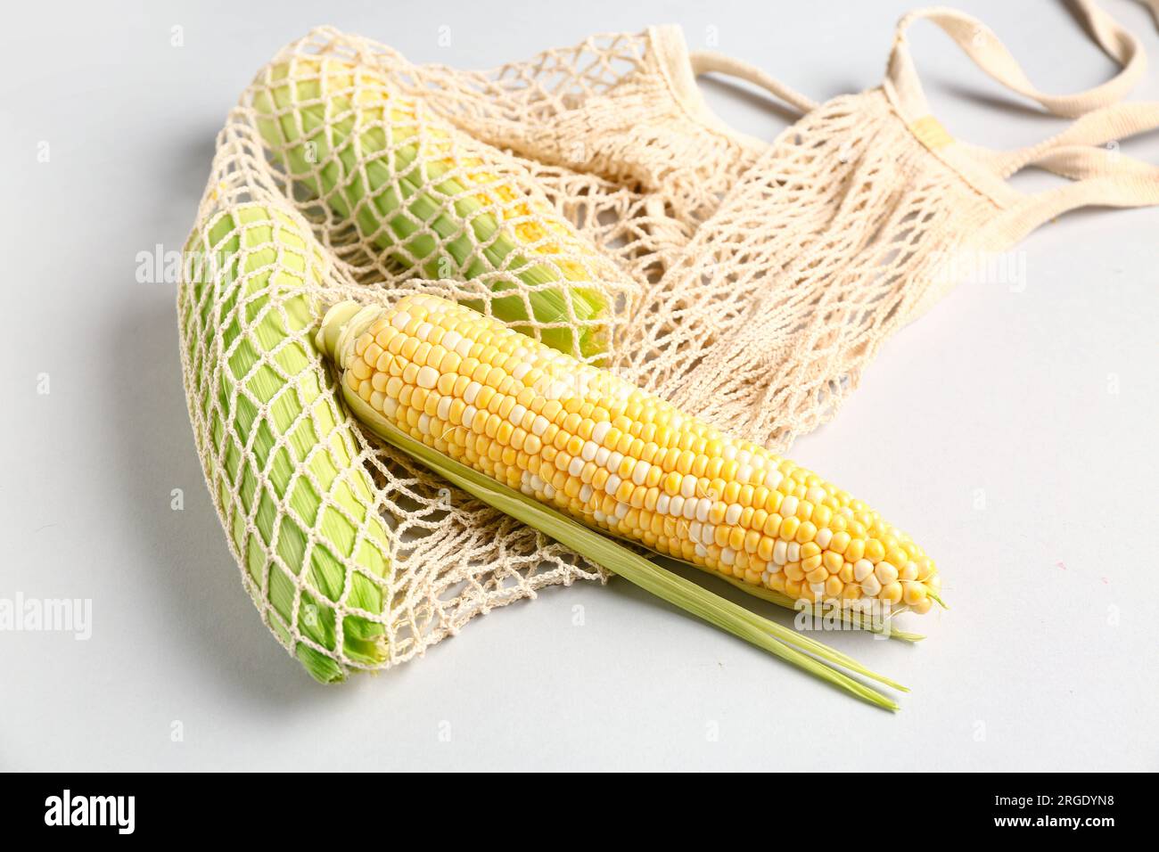 String bag with fresh corn cobs on white background Stock Photo - Alamy