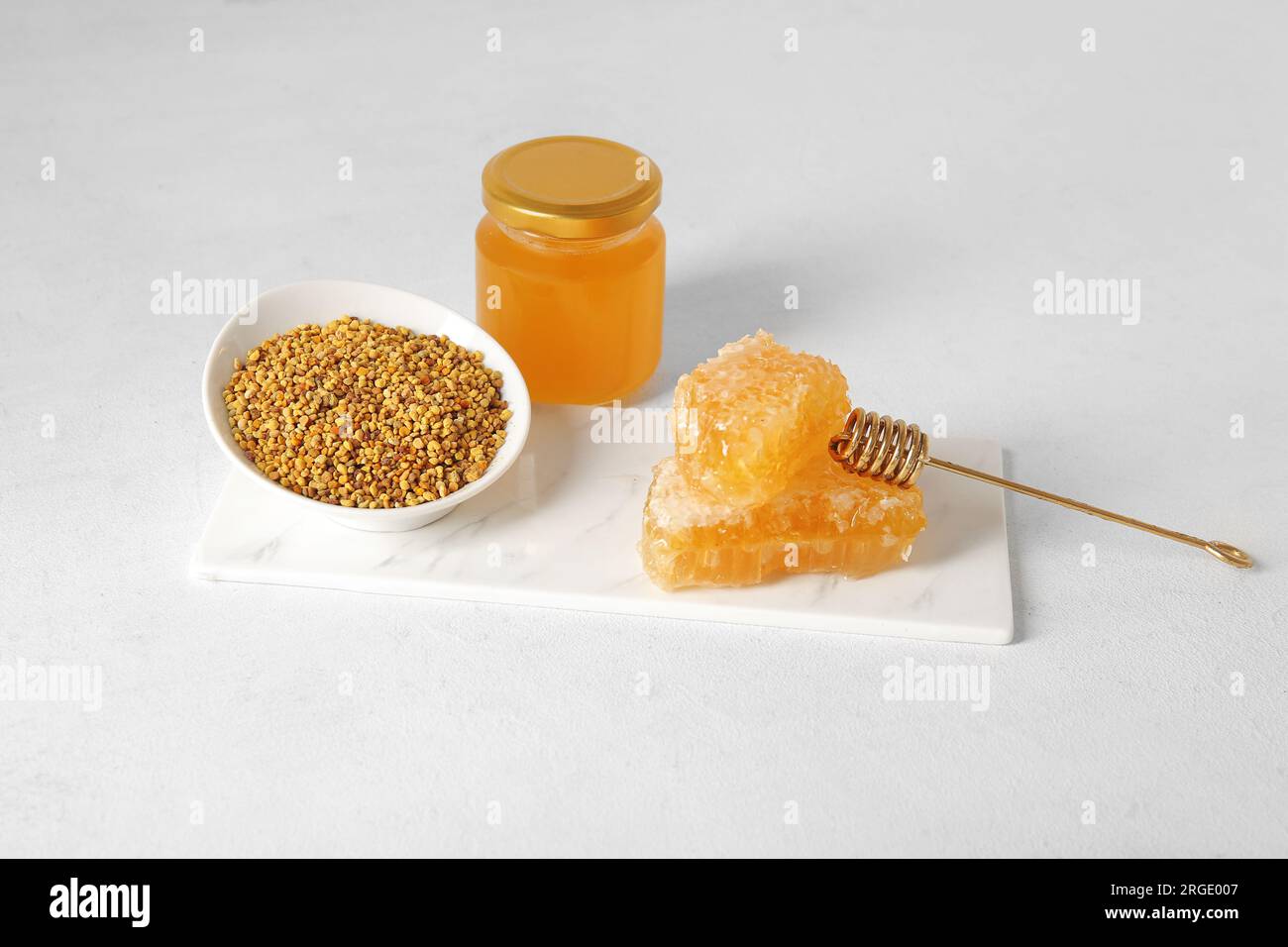 Board with bowl of bee pollen, honey and combs on light background ...