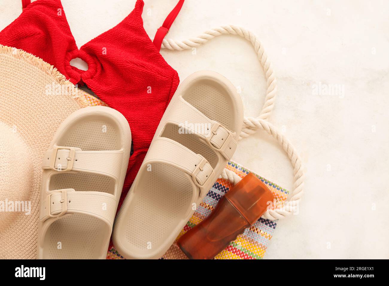 Pair of beige flip flops with swimsuit and hat on white background ...