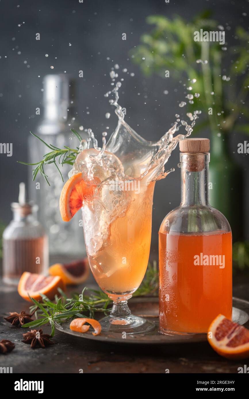 Action splash shot of ice falling into blood orange cocktail in vintage ...