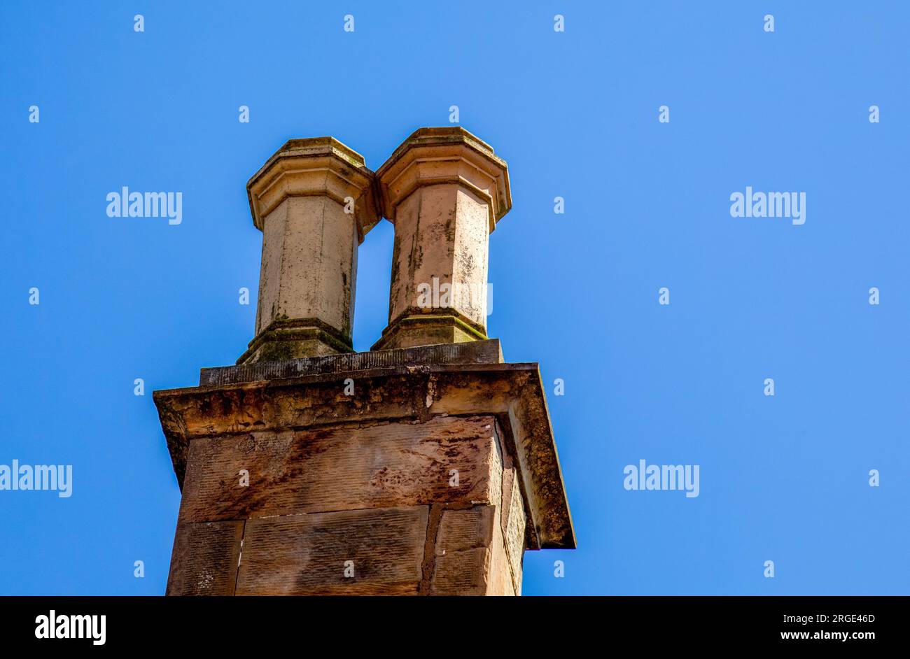 Double chimney pot against a bright blue cloudless sky in the sunshine ...