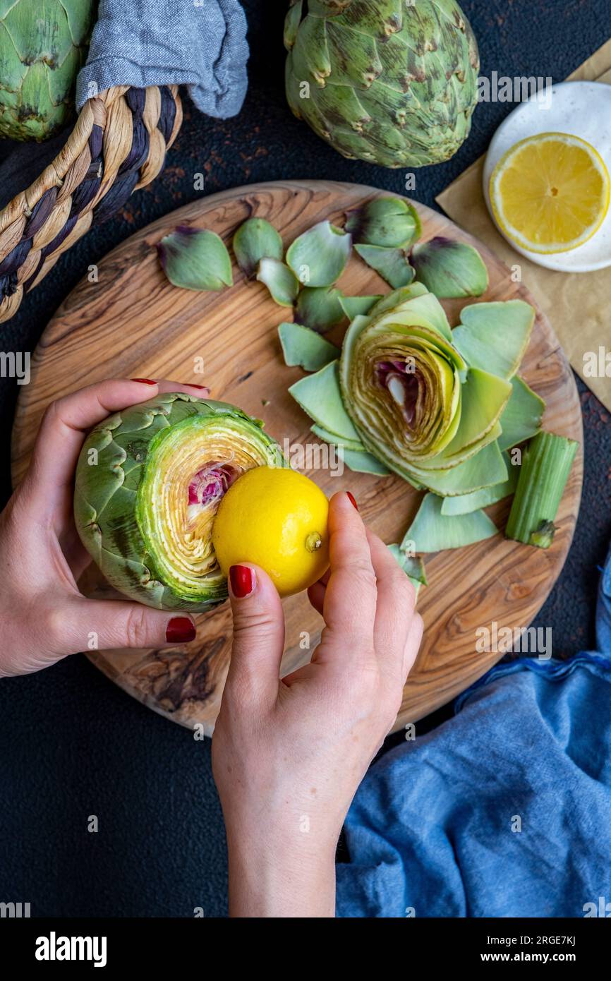 Woman hands rubbing the cut side of an artichoke with lemon Stock Photo ...