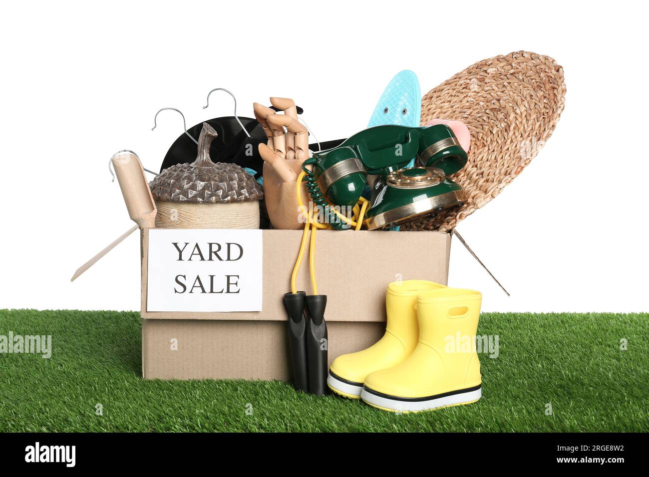 Sign Yard Sale written on box with different stuff on green grass ...