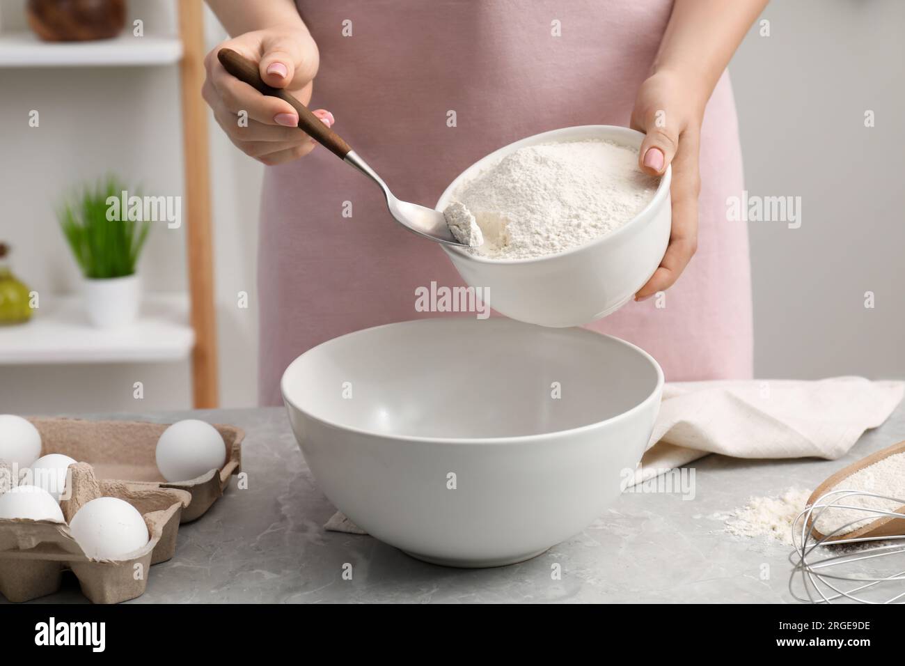 Preparing tasty baklava. Woman putting flour into bowl at light grey ...