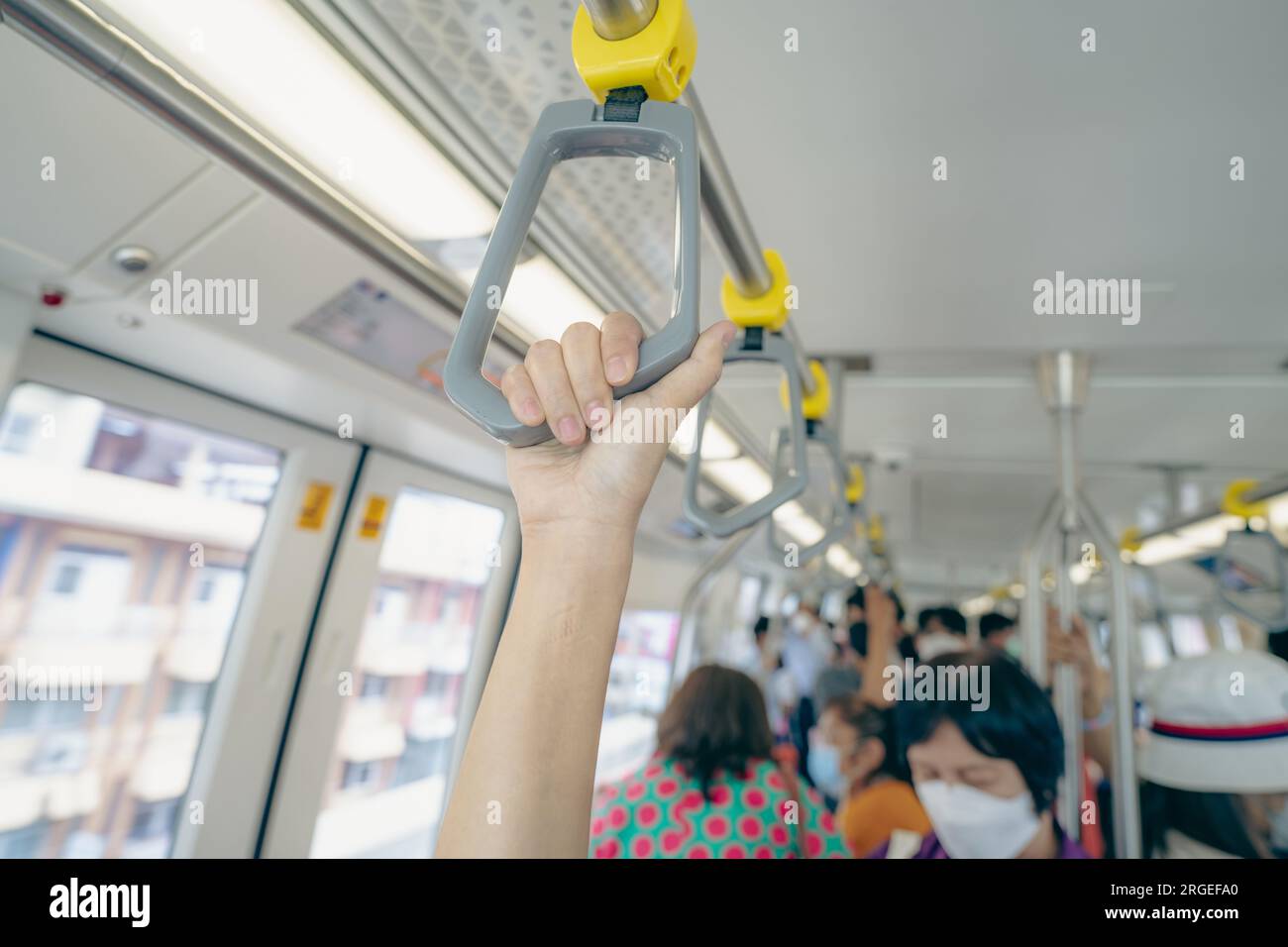 Woman hand firm grip safety handrail in elevated monorail train. Mass transit system in modern ...