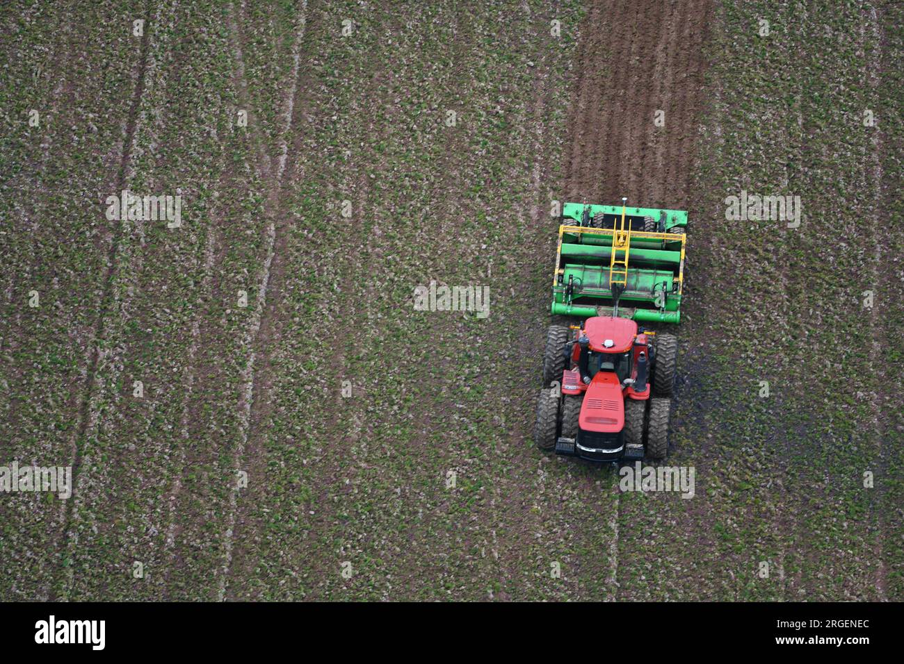 Red tractor pulling agricultural equipment on the farm, engaged in ...