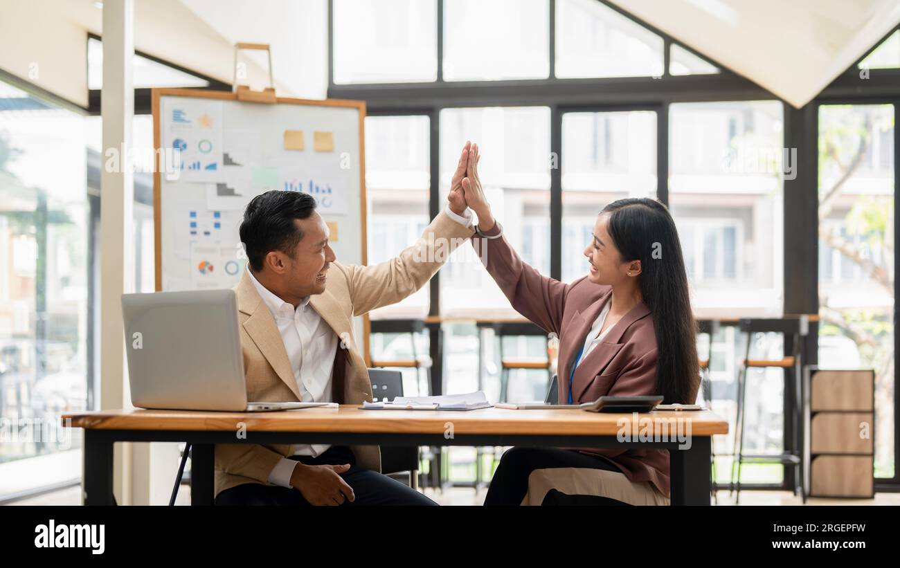 A happy and professional Asian businessman is giving high fives to a ...