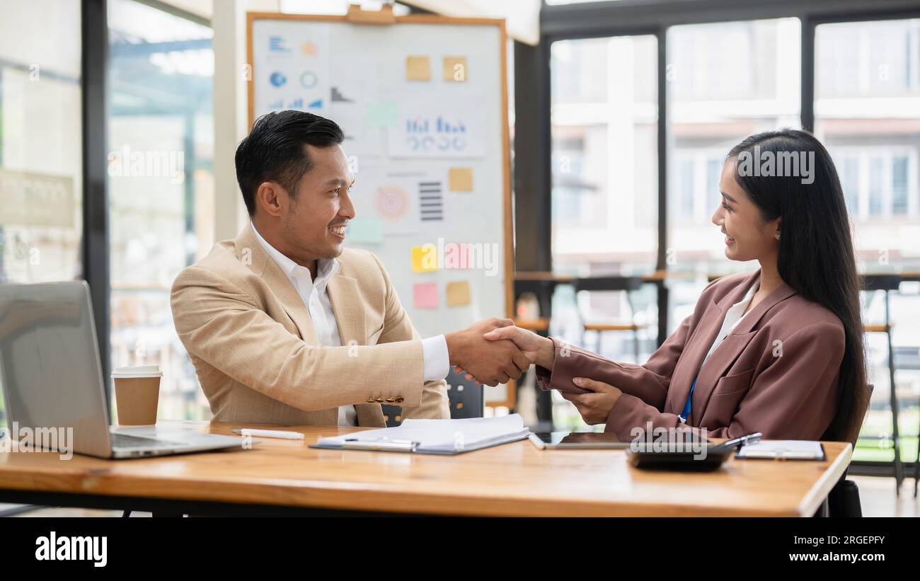 A professional Asian businessman is shaking hands with a female ...