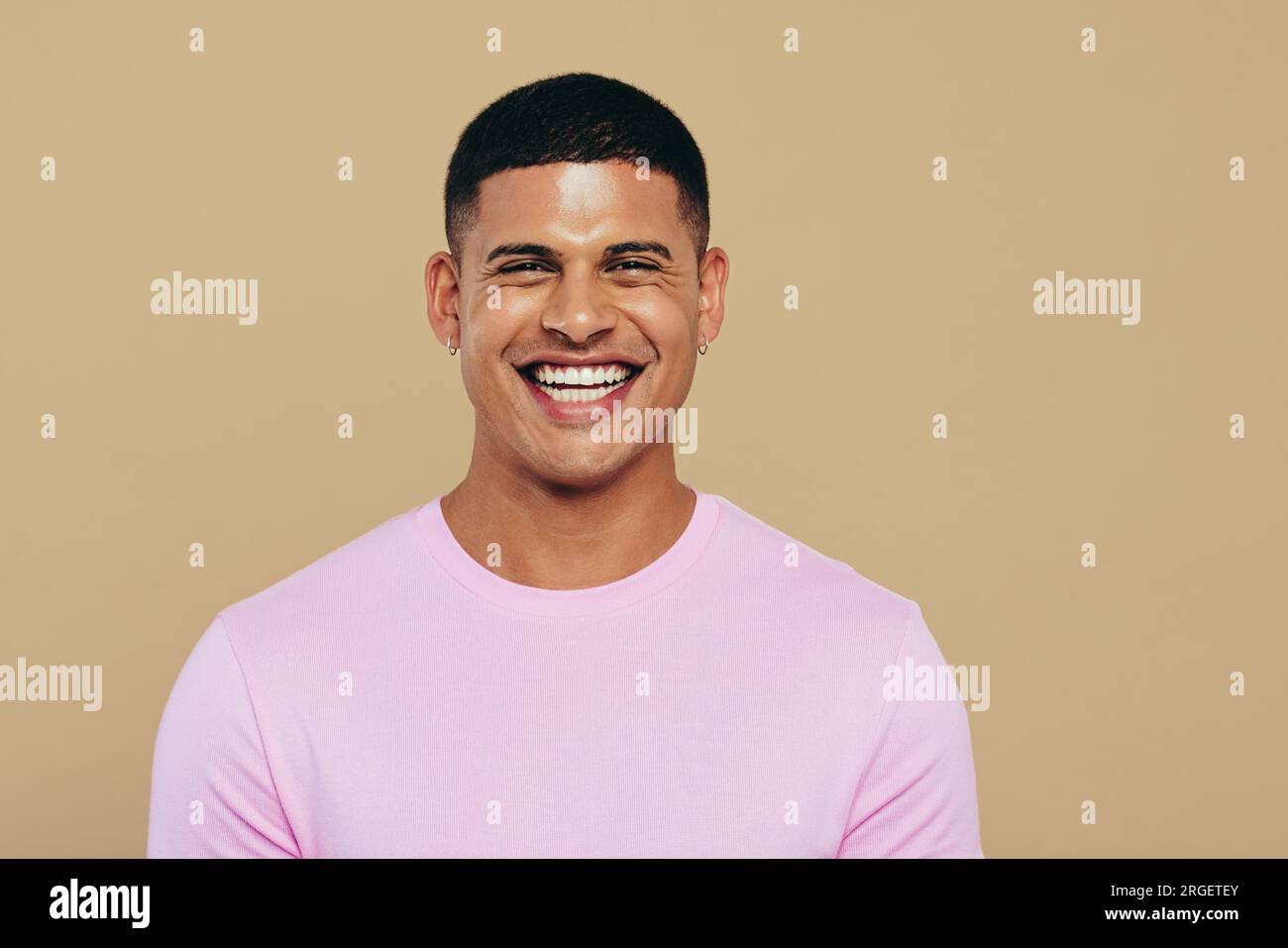 Portrait of a young man smiling at the camera with confidence, showing ...