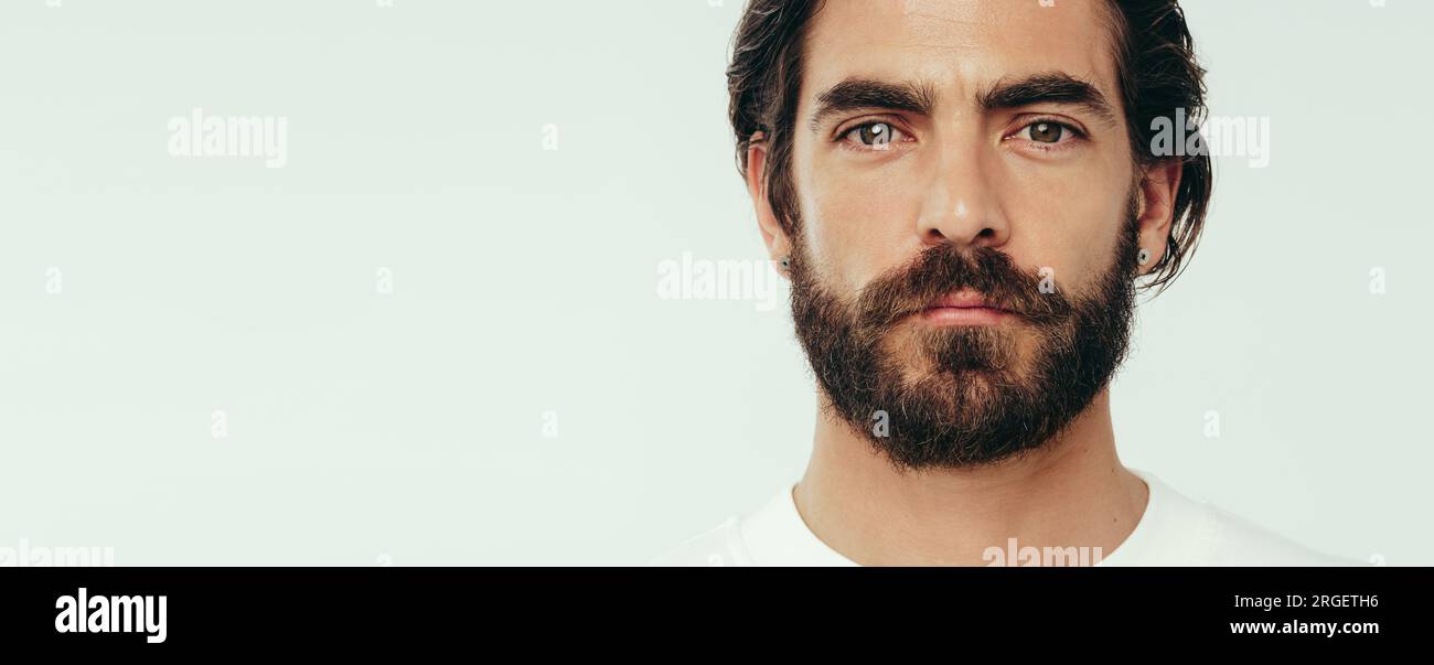 Confident young man with glowing and healthy skin standing in a studio ...