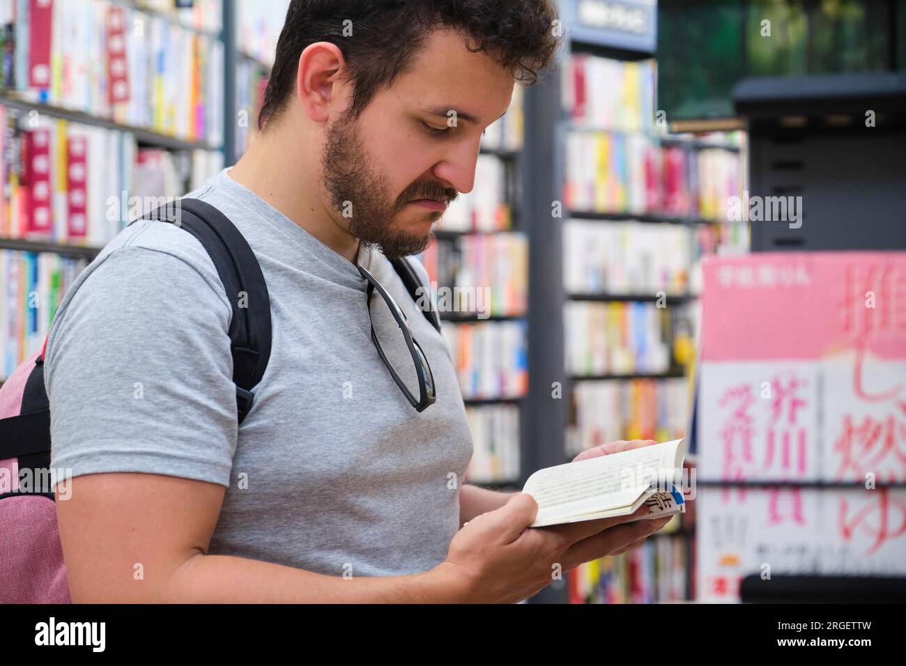 Latin tourist try to read a comic at a Japanese comic store in Tokyo ...