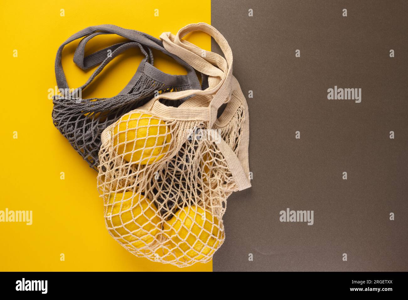 Brown and ecru mesh net bags with lemons and copy space on brown and ...