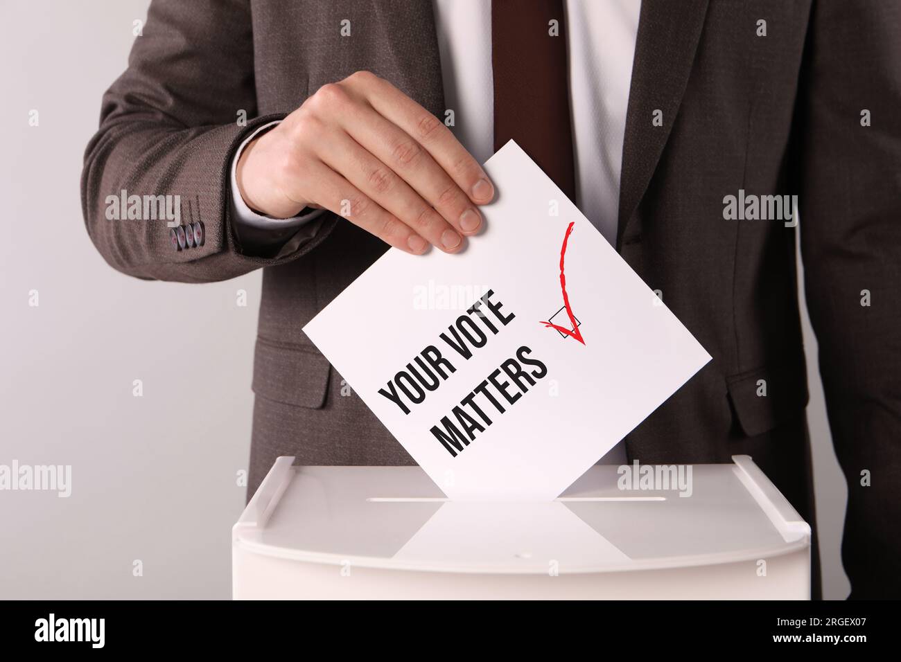 Man putting paper with text Your Vote Matters and tick into ballot box ...