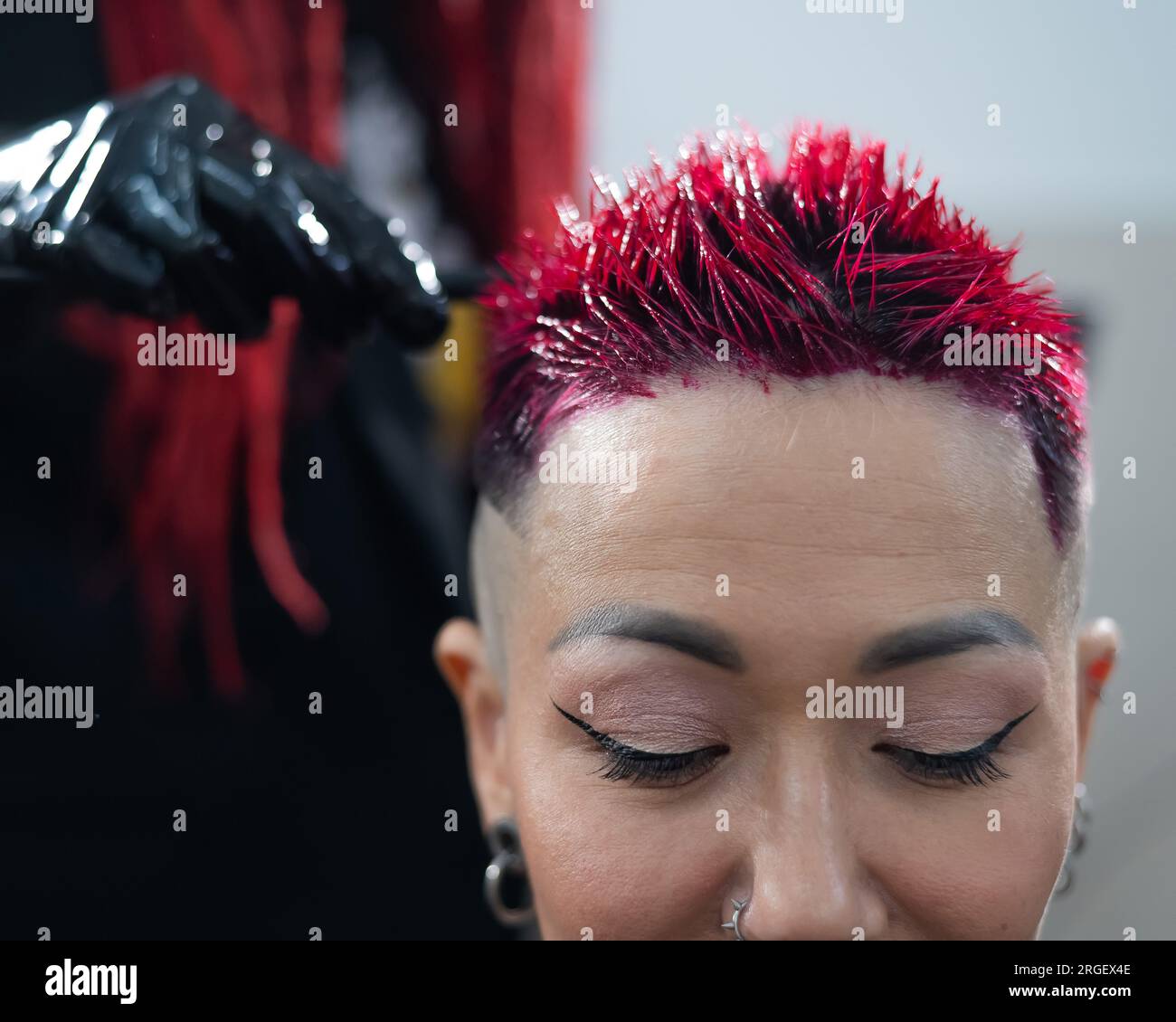 The hairdresser dyes the hair of an Asian woman in pink. Short extreme ...