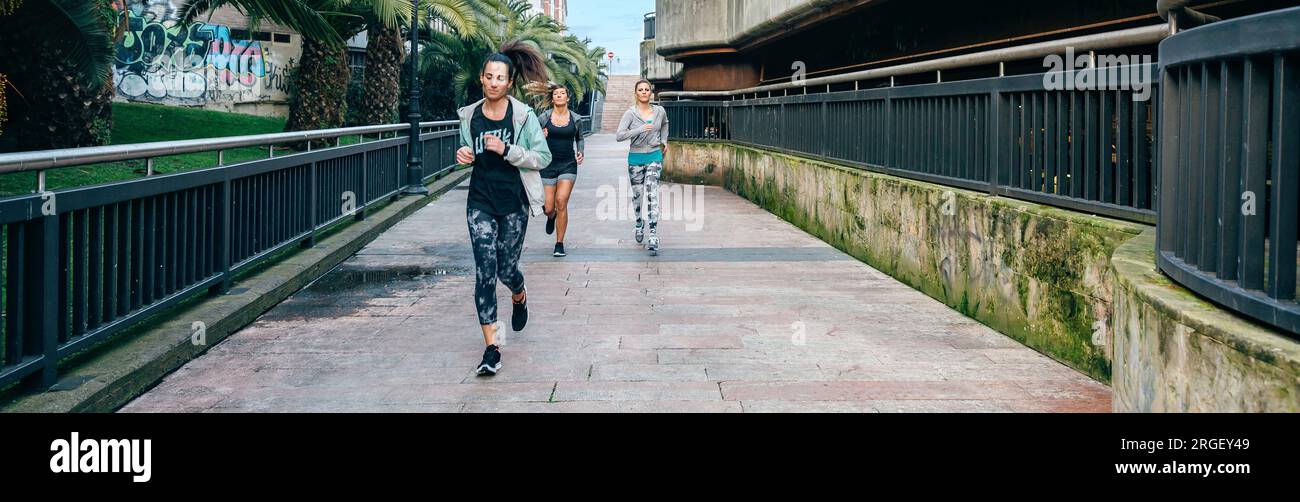 Group of young women friends runners training over a urban runway with ...