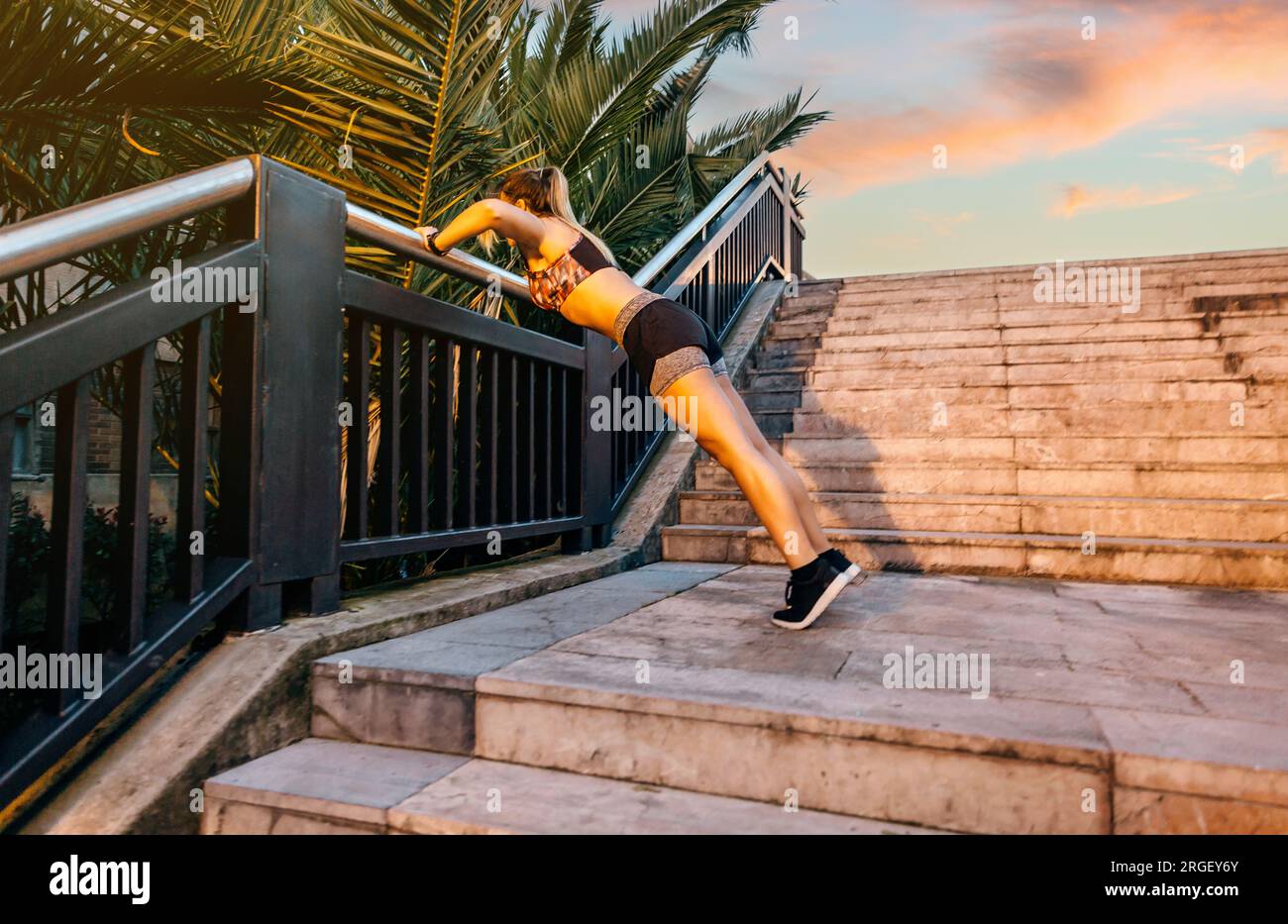 Unrecognizable young blonde woman doing doing push ups over railing ...