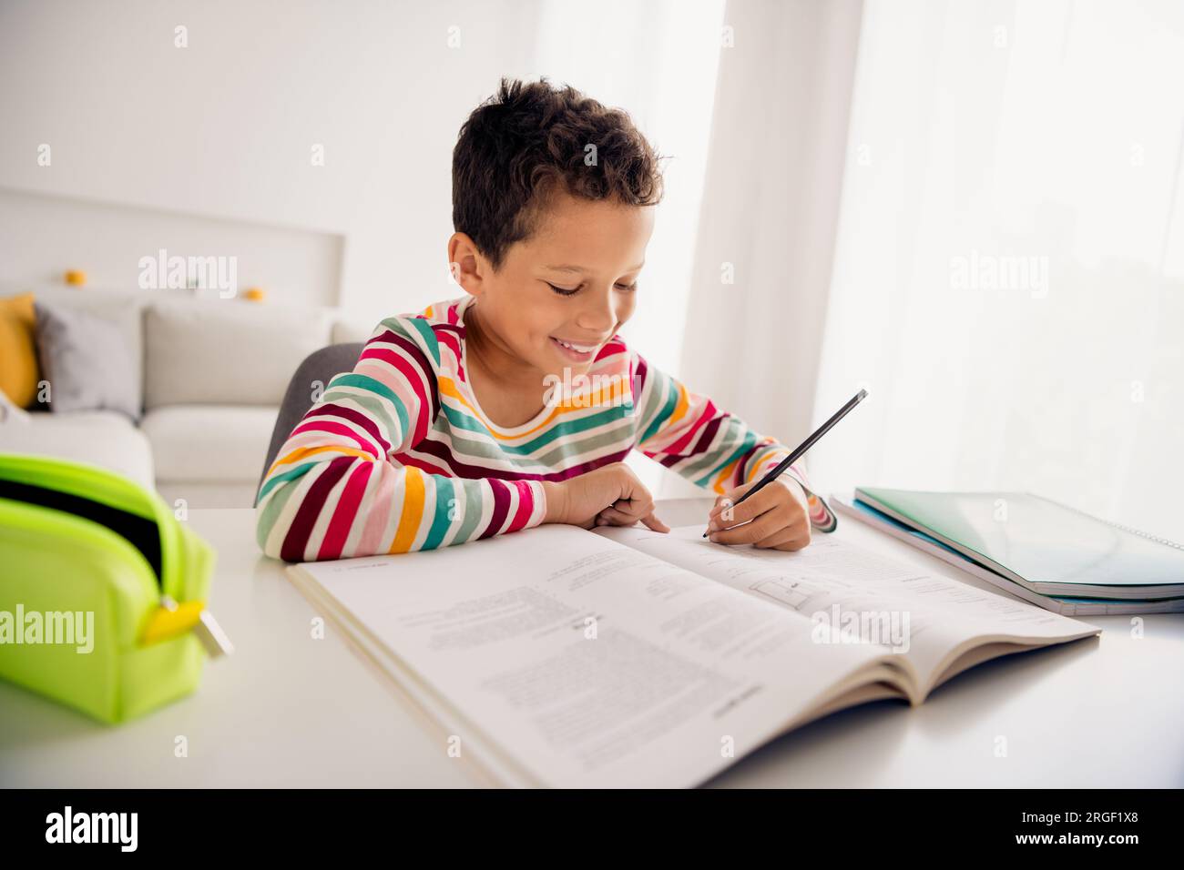 Photo cadre of small boy preteen age writing do homework using copybook ...