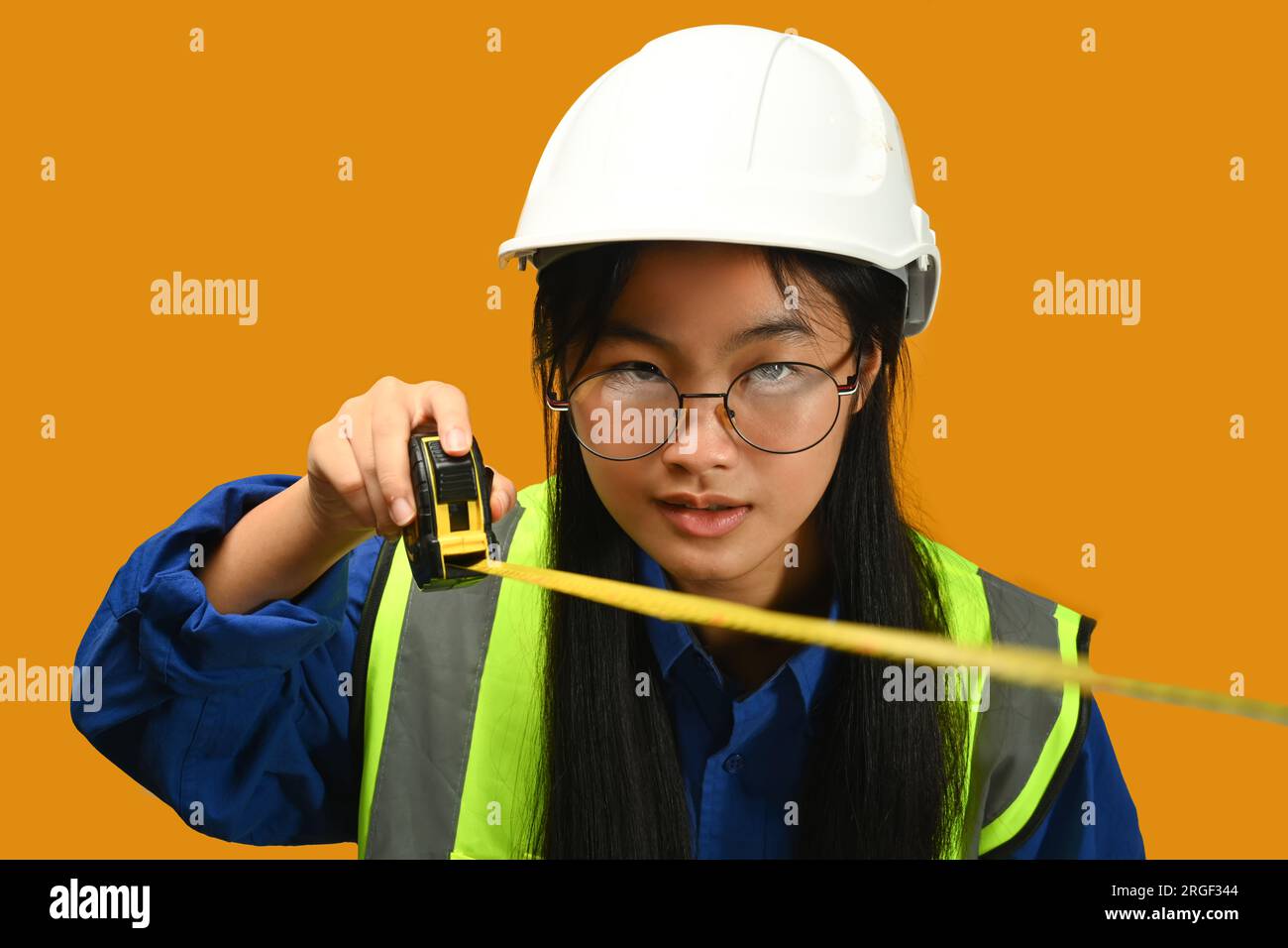 Portrait of Asian girl posing as an engineer or architect on yellow ...