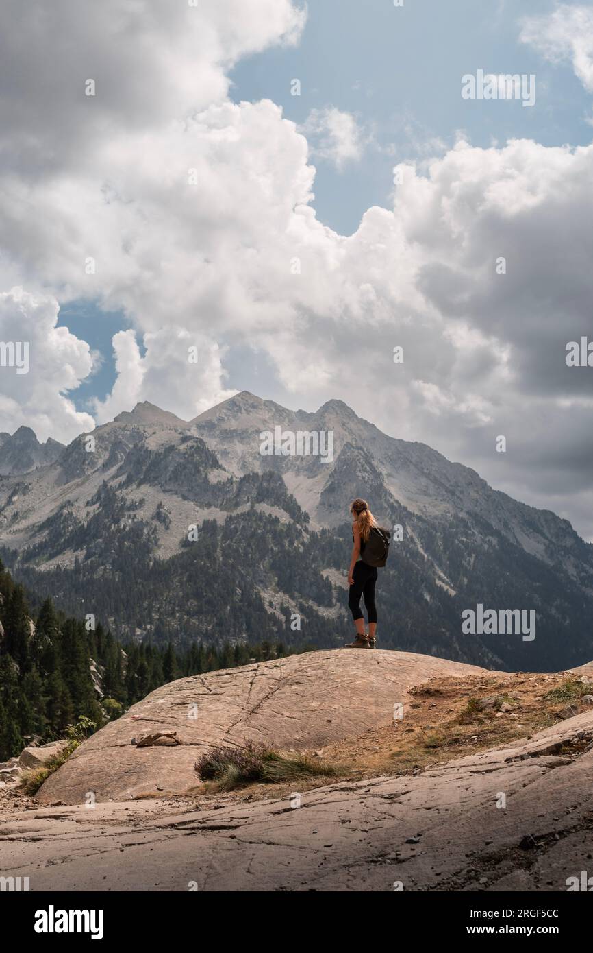 Mountain landscape with a woman on a rock observing the peaks of the ...