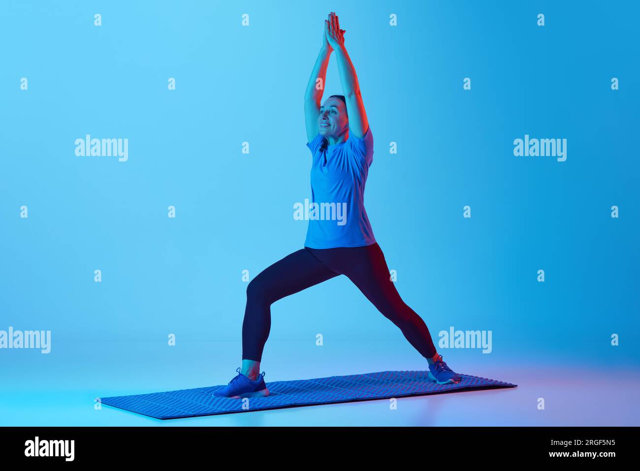 Keeping body toned. Woman training on fitness matt, stretching against ...