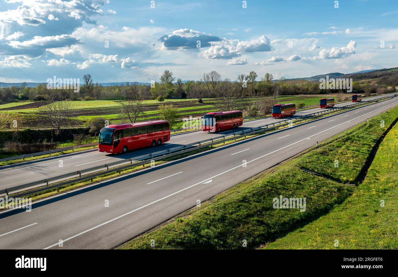 Series of modern red modern buses traveling on a wide highway in a ...